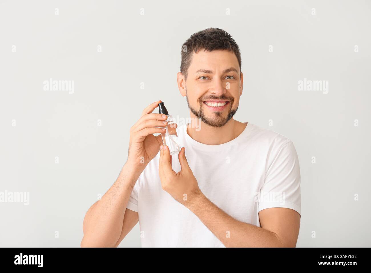 Handsome man with cosmetic product on white background Stock Photo - Alamy