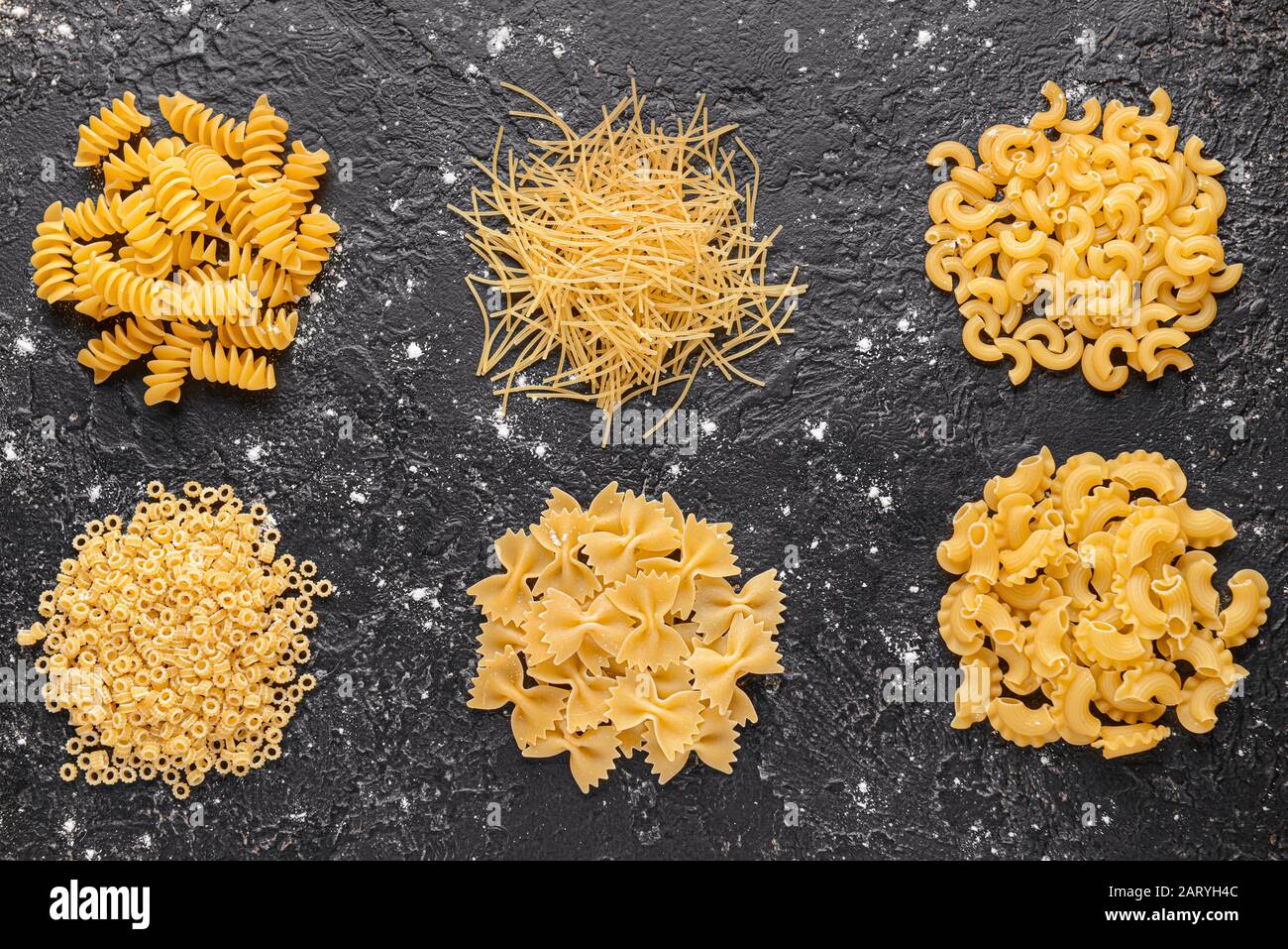 Different uncooked pasta on dark background Stock Photo - Alamy