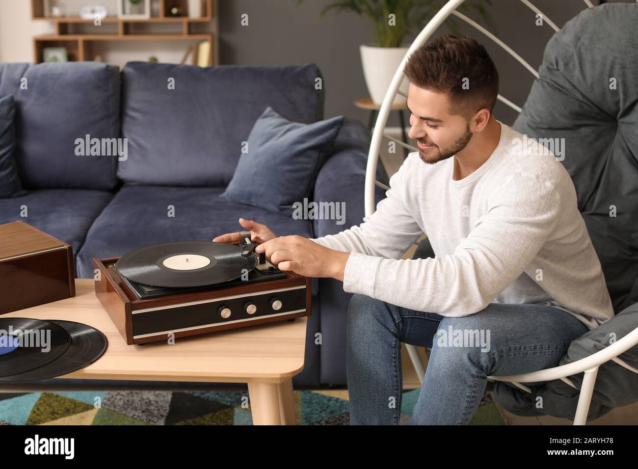 Young man listening to music through record player at home Stock Photo ...