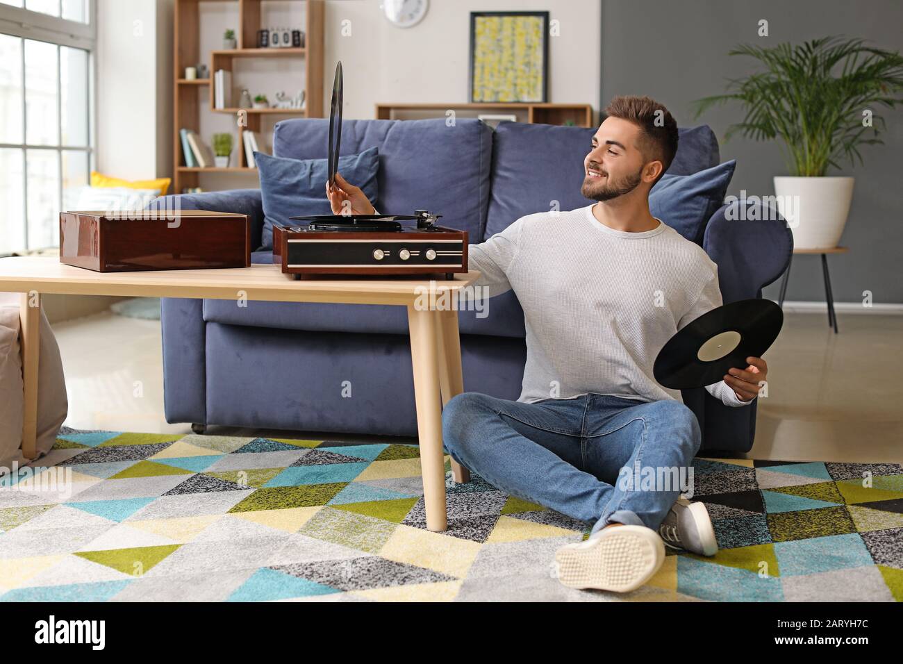Young man listening to music through record player at home Stock Photo ...