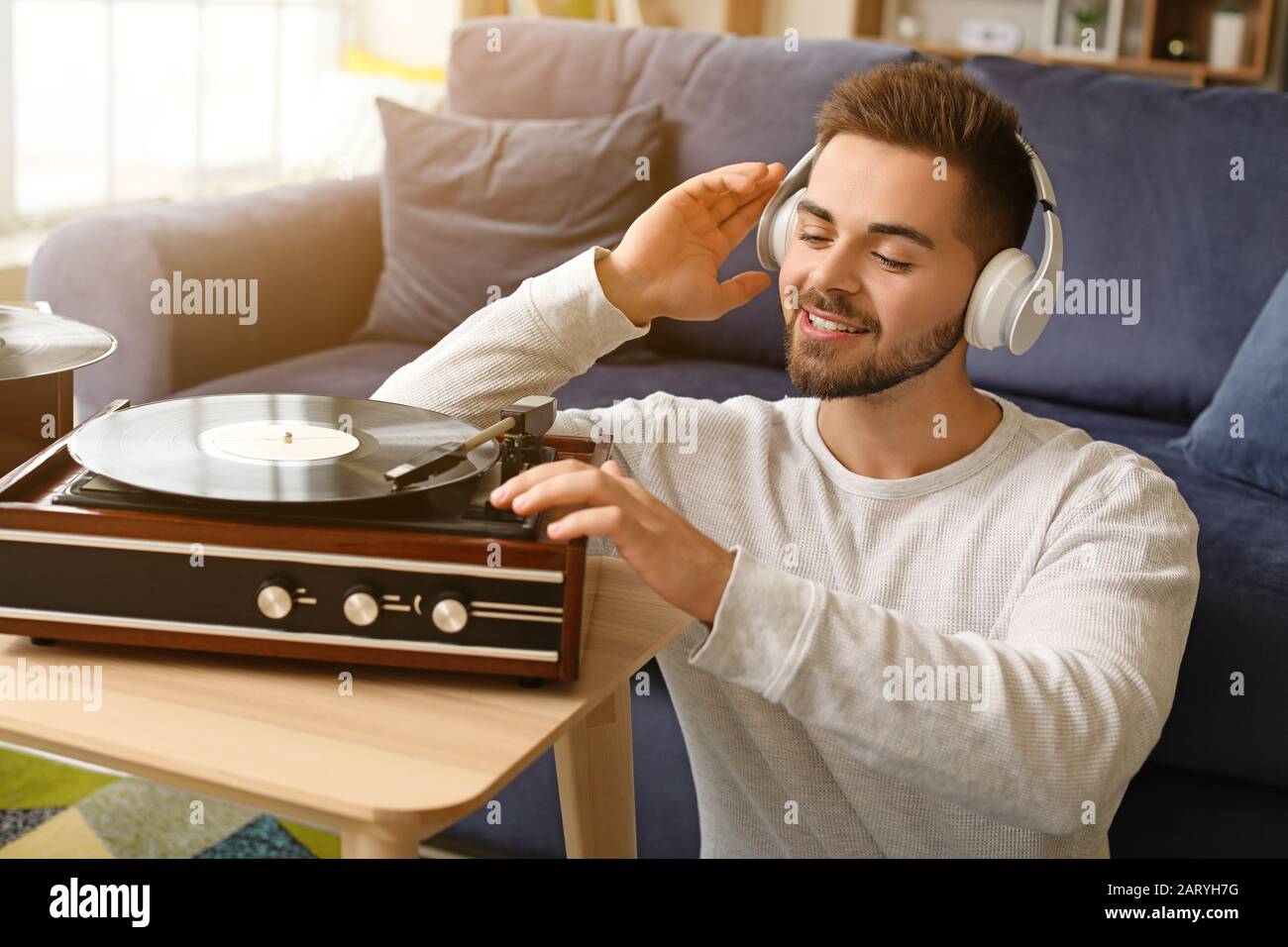 Young man listening to music through record player at home Stock Photo ...