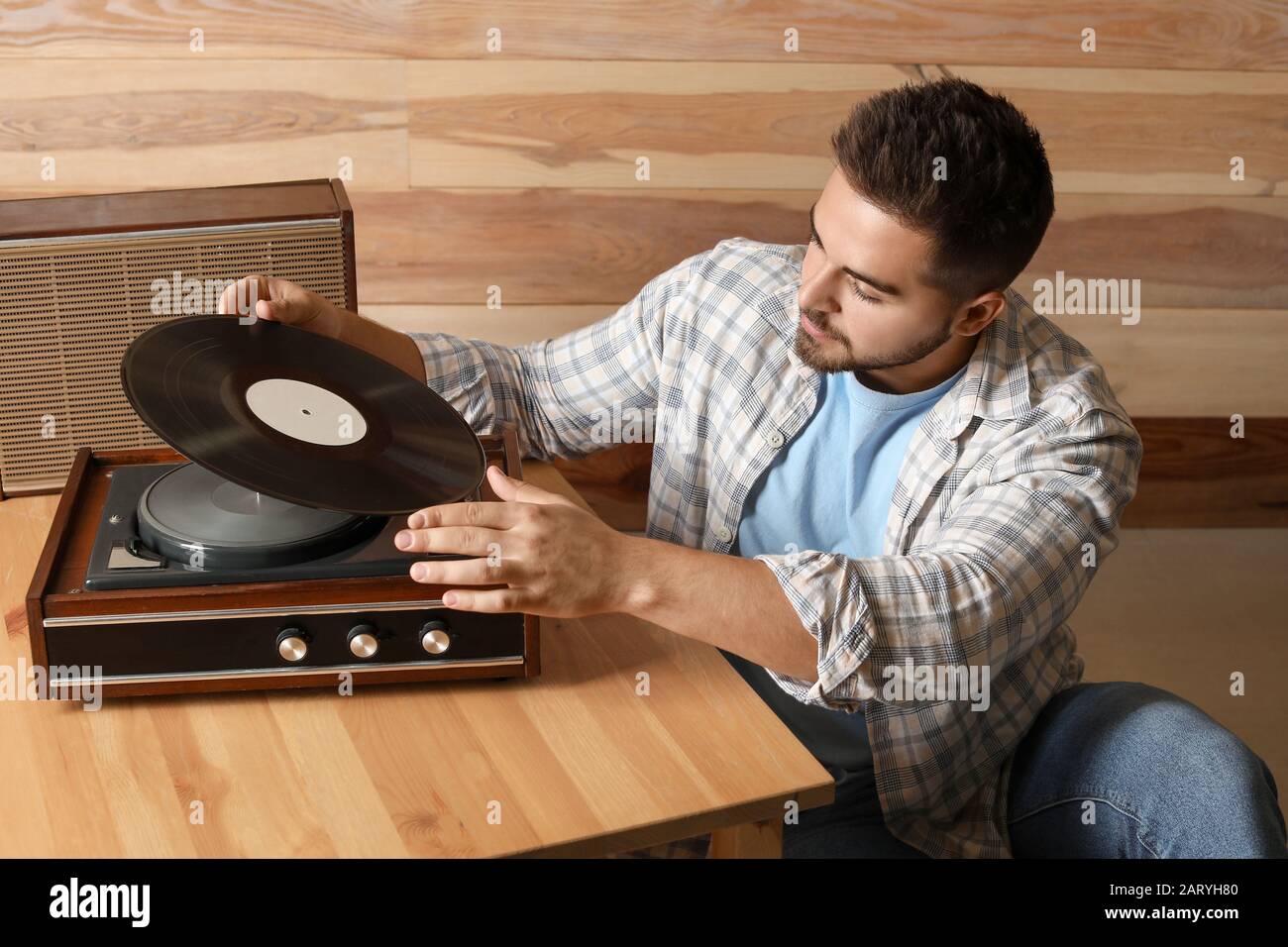 Young man listening to music through record player at home Stock Photo ...