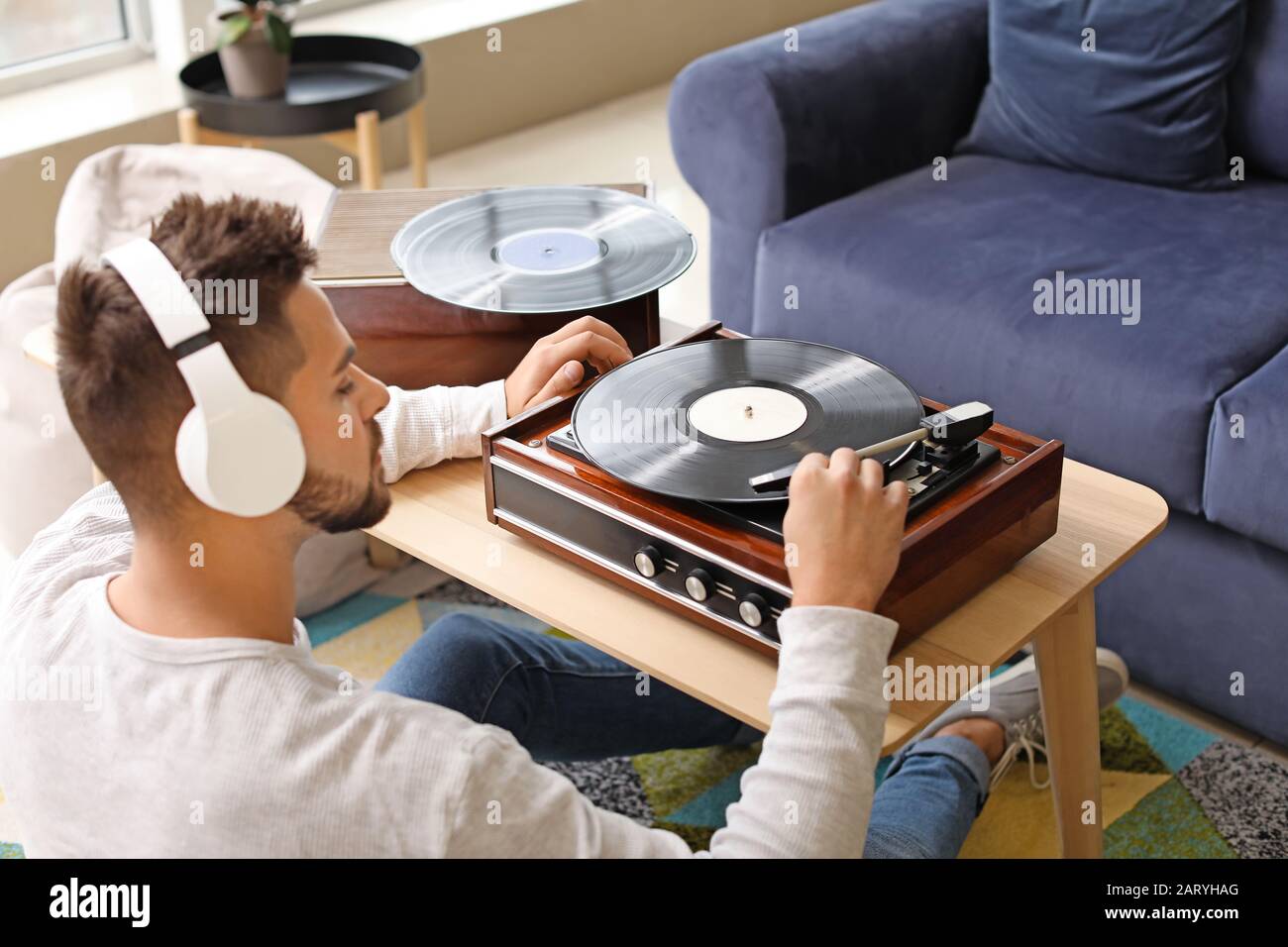 Young man listening to music through record player at home Stock Photo ...
