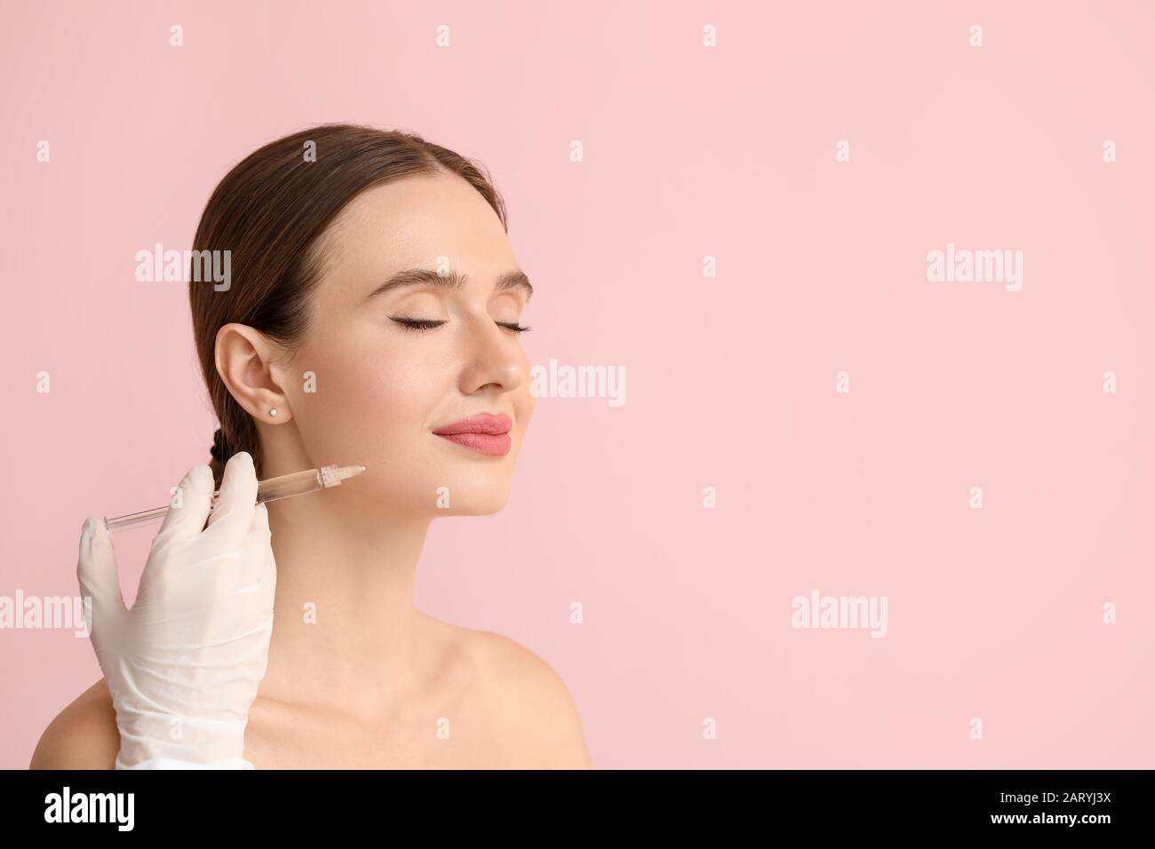 Young woman receiving filler injection against color background Stock ...