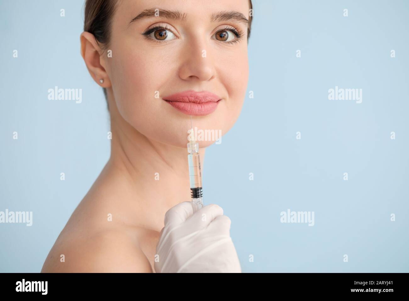 Young woman receiving filler injection against color background Stock ...