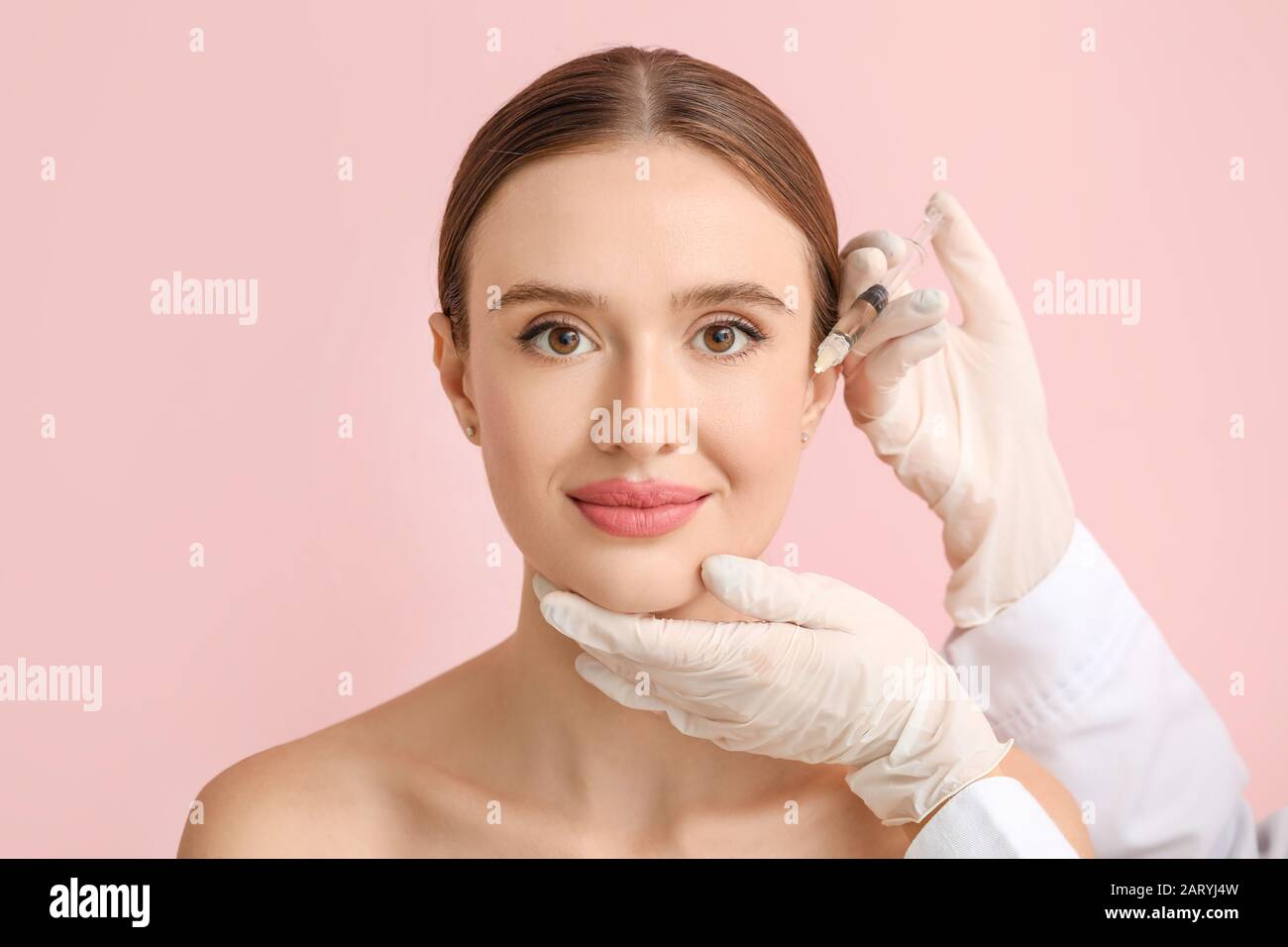 Young woman receiving filler injection against color background Stock ...
