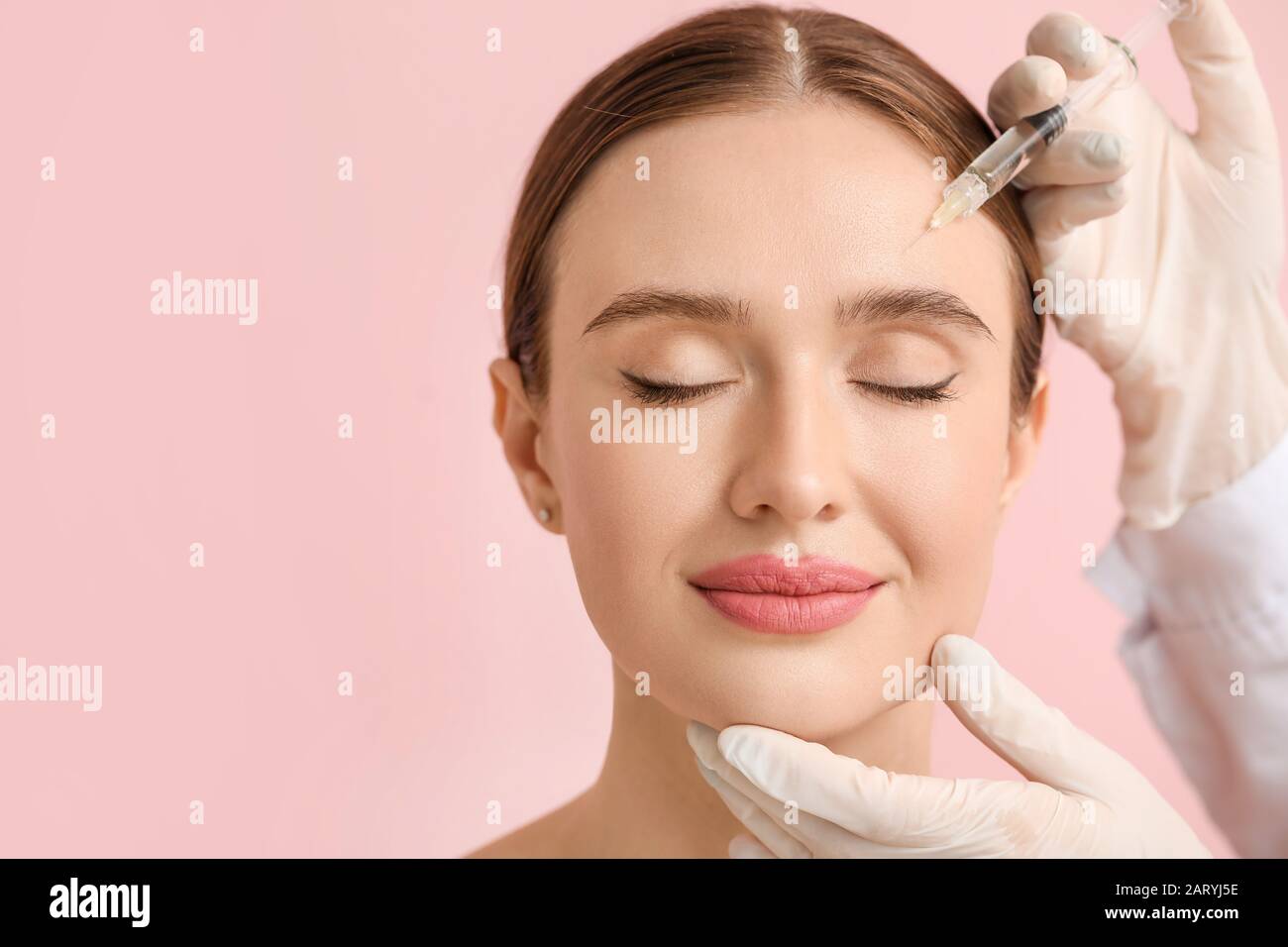 Young woman receiving filler injection against color background Stock ...