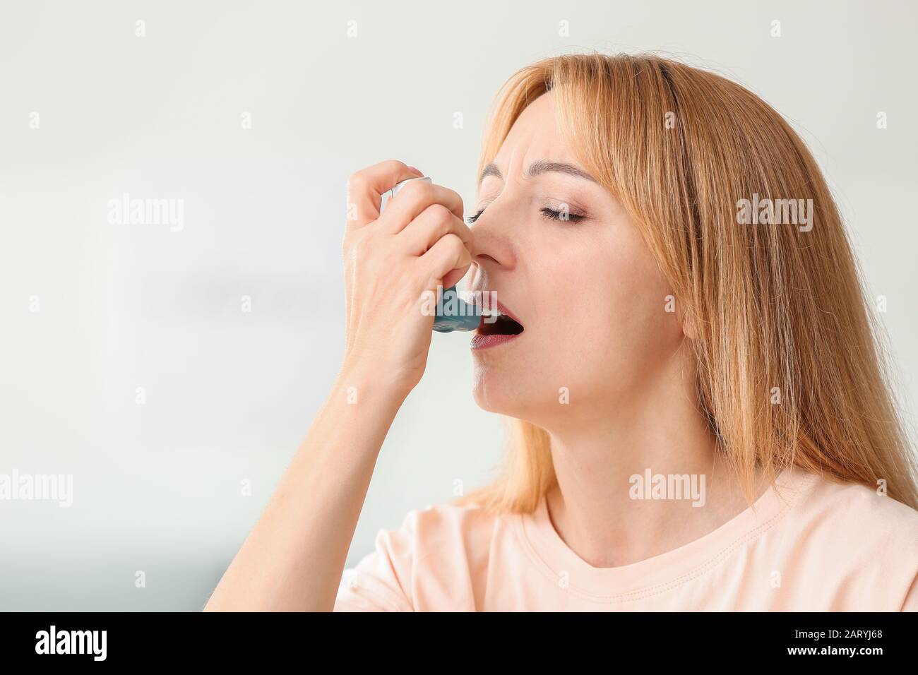 Beautiful mature woman with asthma inhaler at home Stock Photo - Alamy