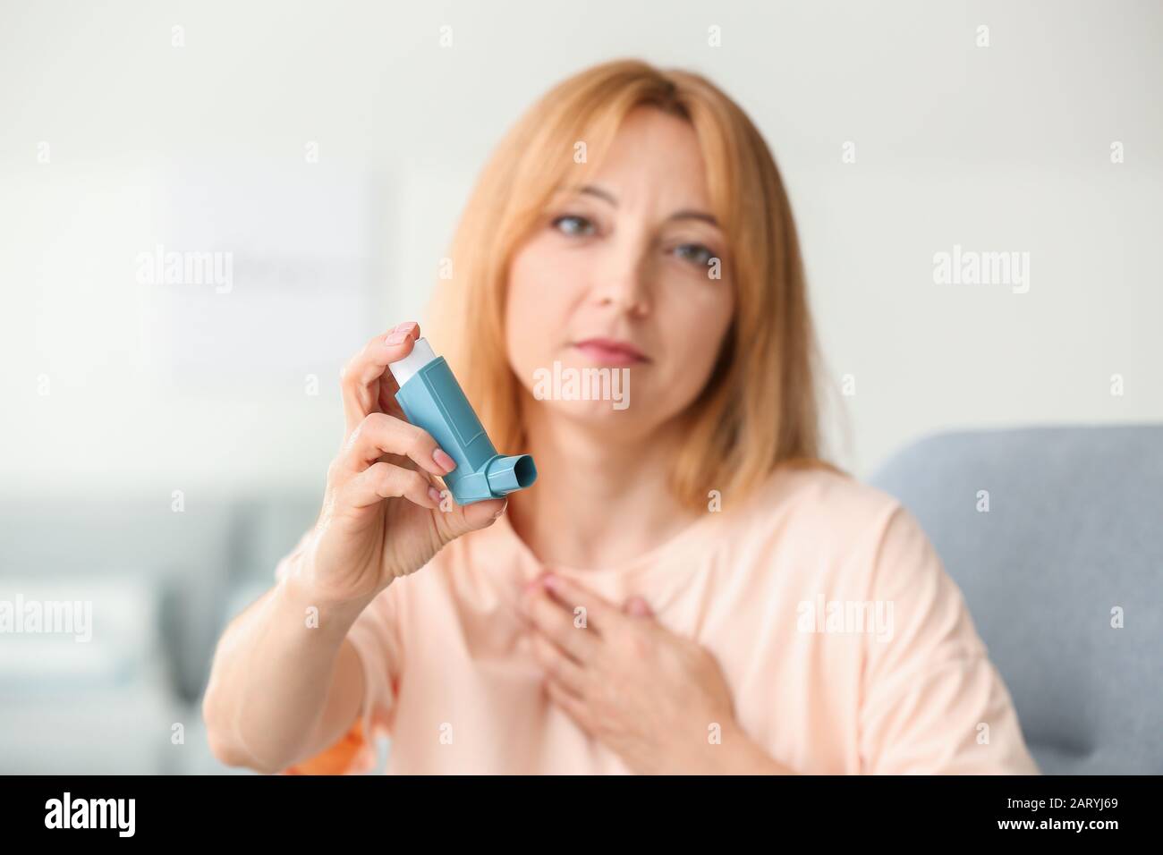 Beautiful mature woman with asthma inhaler at home Stock Photo - Alamy