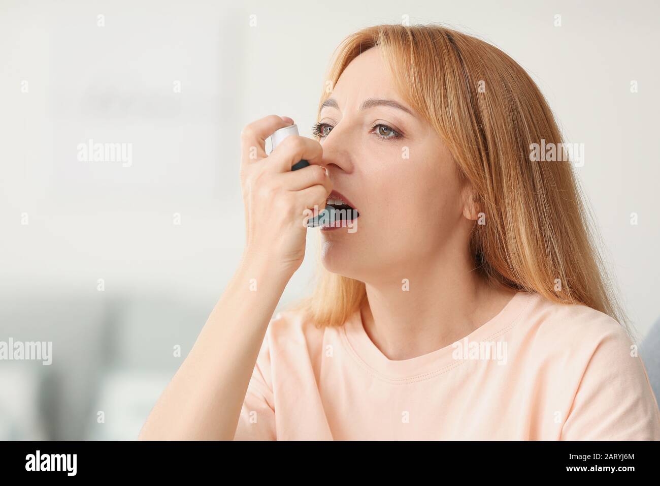 Beautiful mature woman with asthma inhaler at home Stock Photo - Alamy