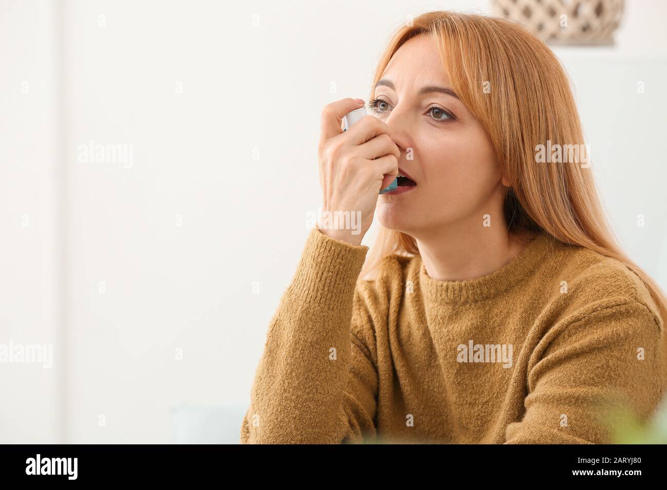 Beautiful mature woman with asthma inhaler at home Stock Photo - Alamy