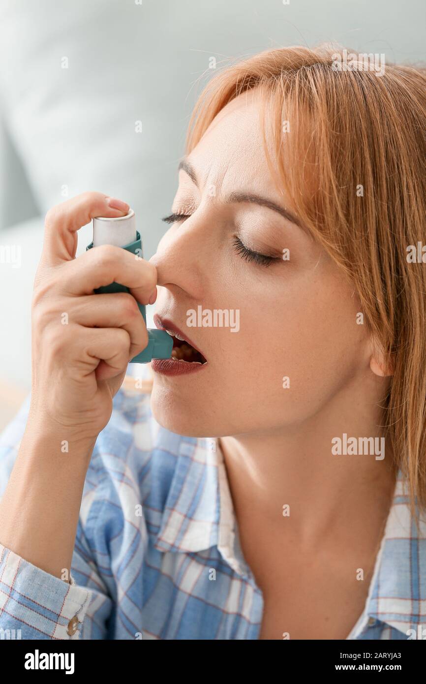 Beautiful mature woman with asthma inhaler at home Stock Photo - Alamy