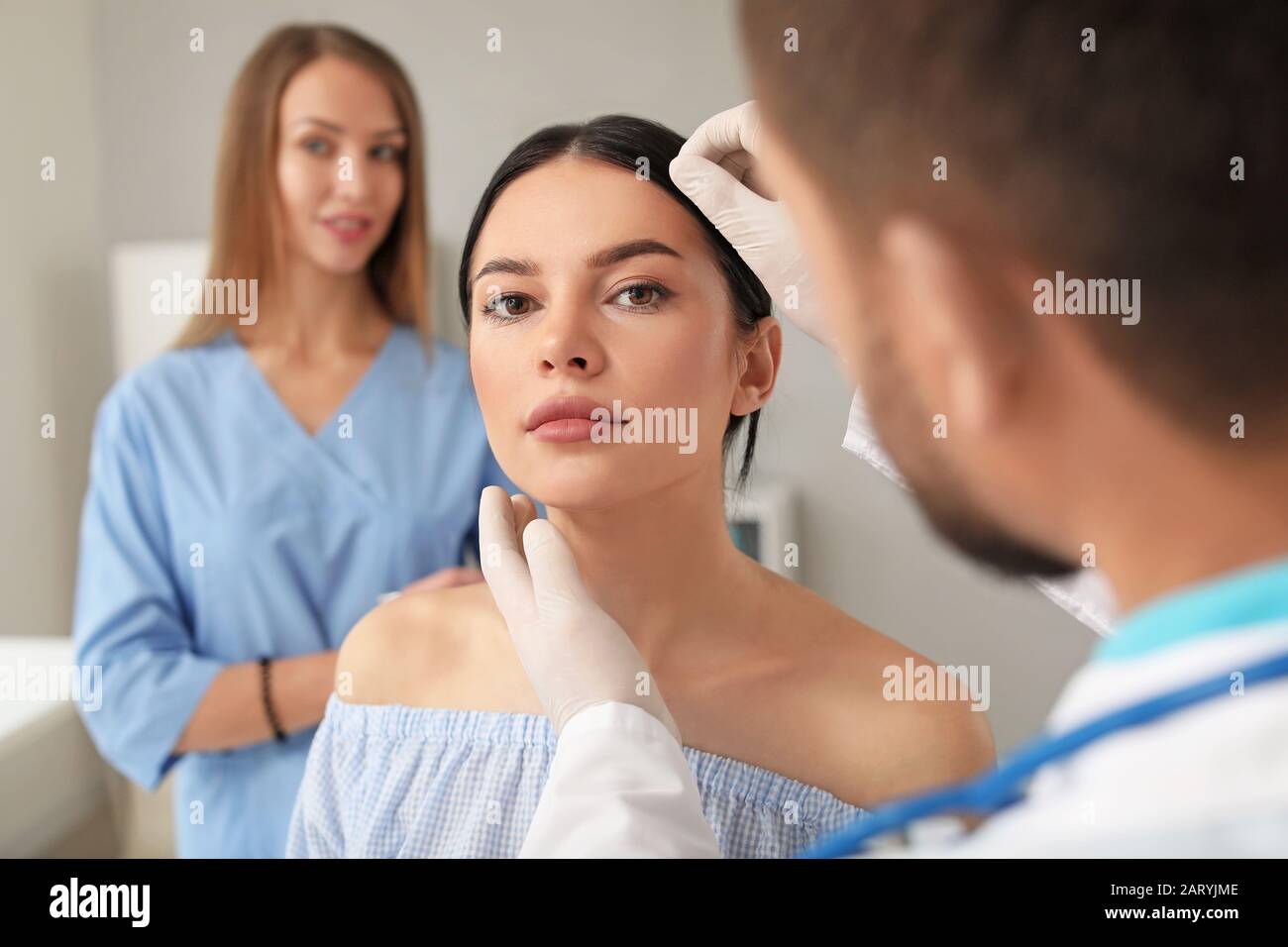 Plastic surgeon examining young woman's face prior to operation in ...