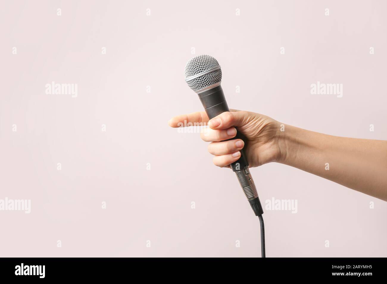 Female hand with microphone on light background Stock Photo - Alamy
