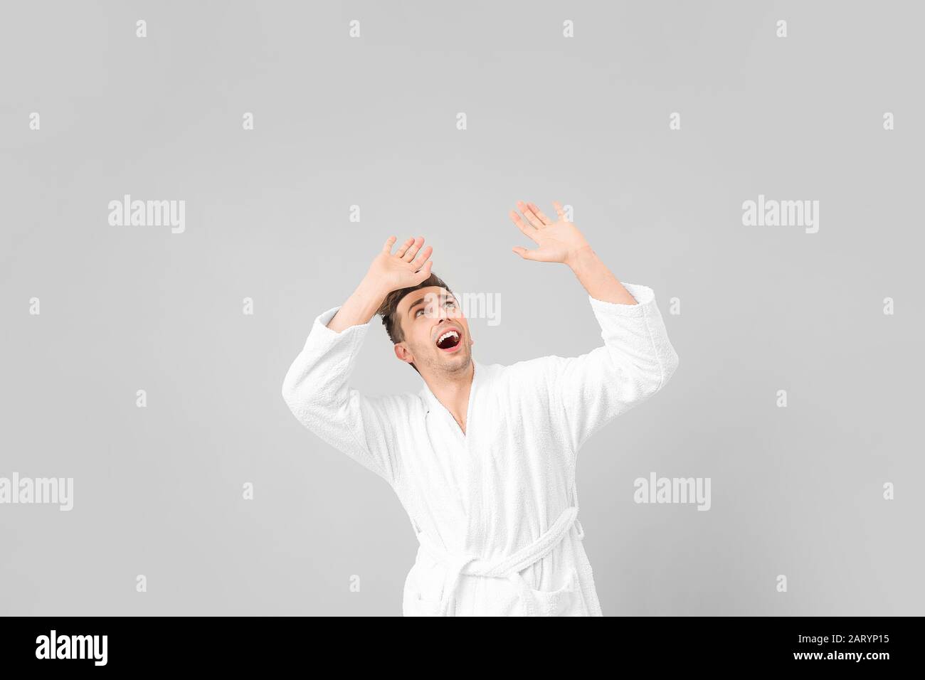 Afraid man in bathrobe on grey background Stock Photo - Alamy
