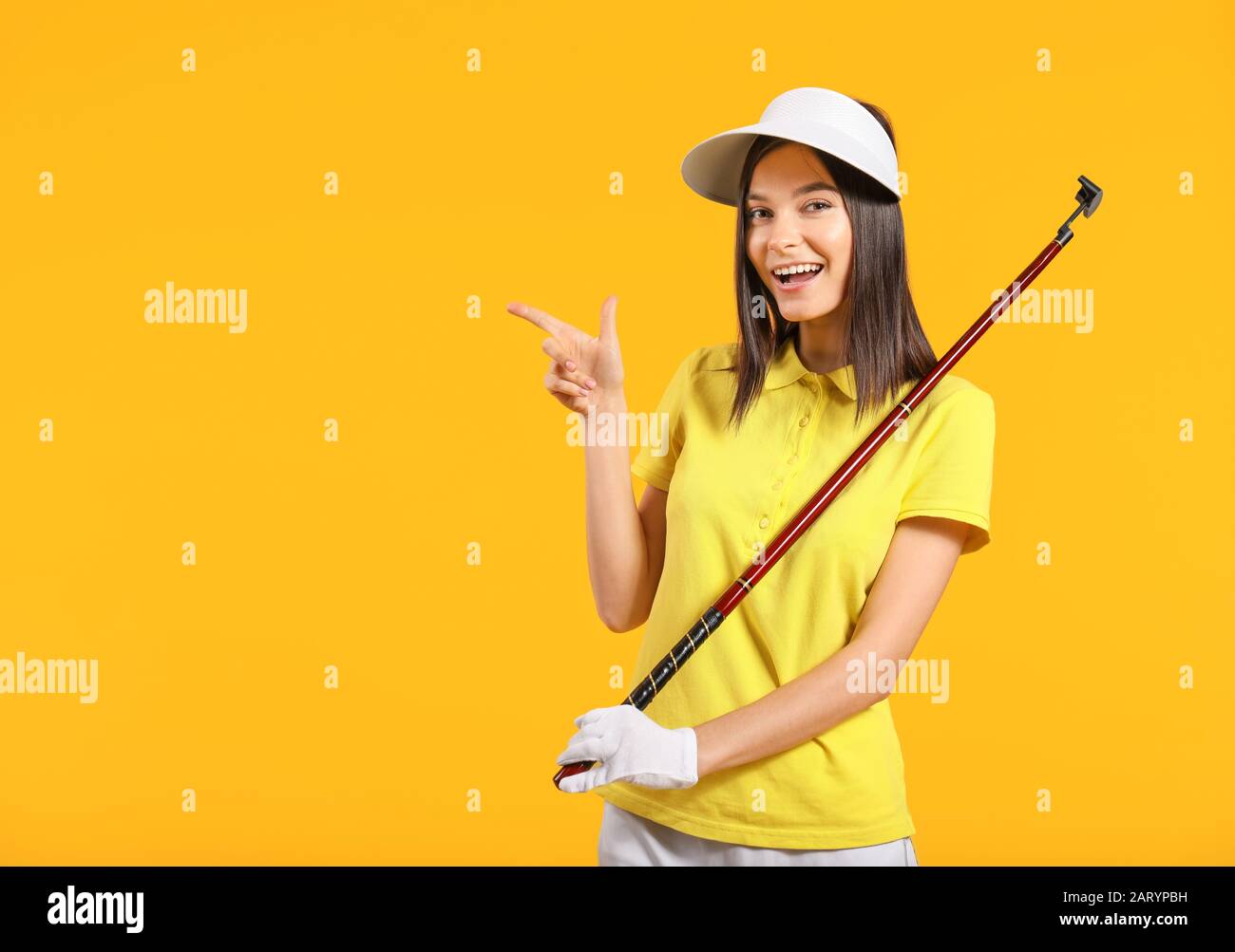 Beautiful female golfer pointing at something on color background Stock ...