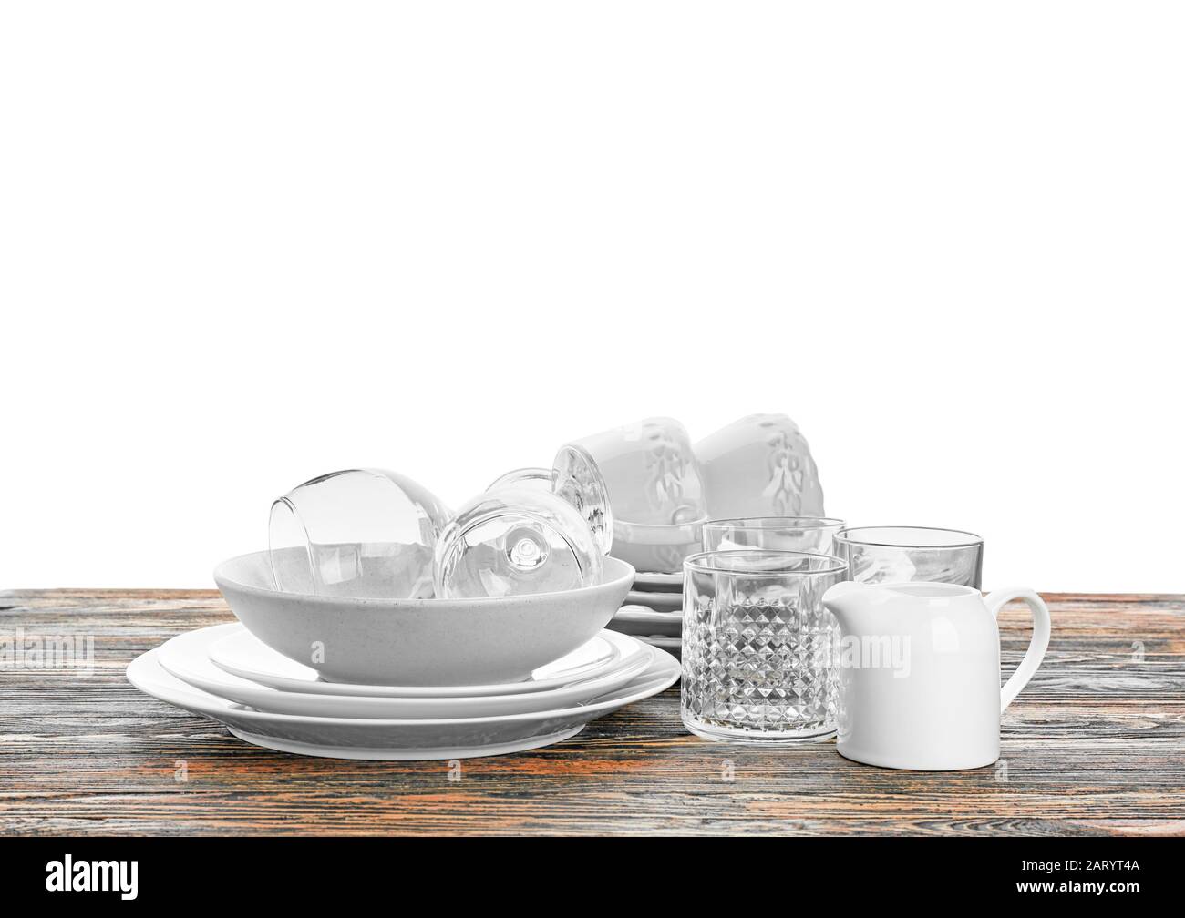 Set of clean dishes on table against white background Stock Photo - Alamy