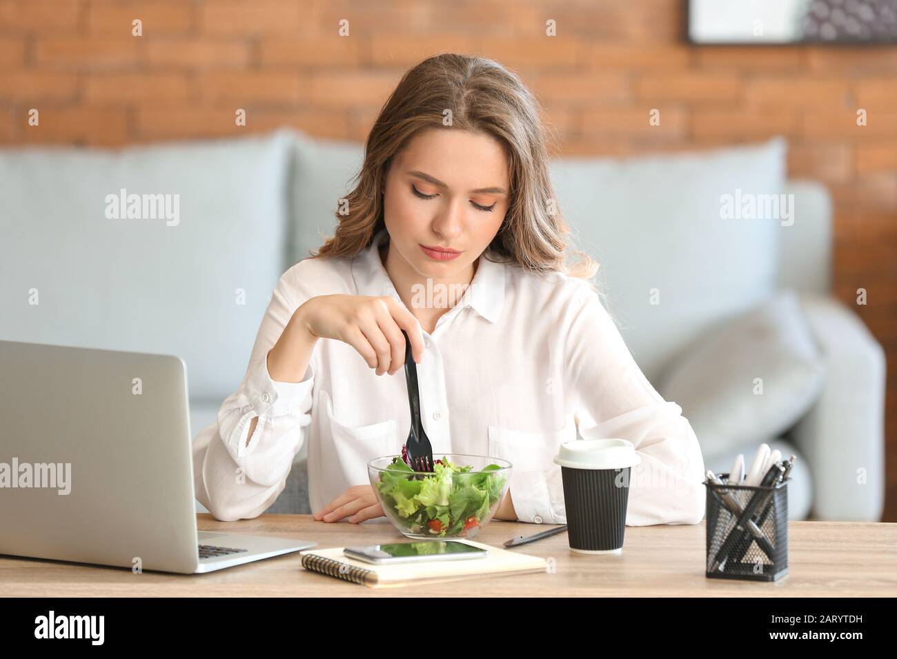 Sad woman with healthy vegetable salad in office Stock Photo - Alamy