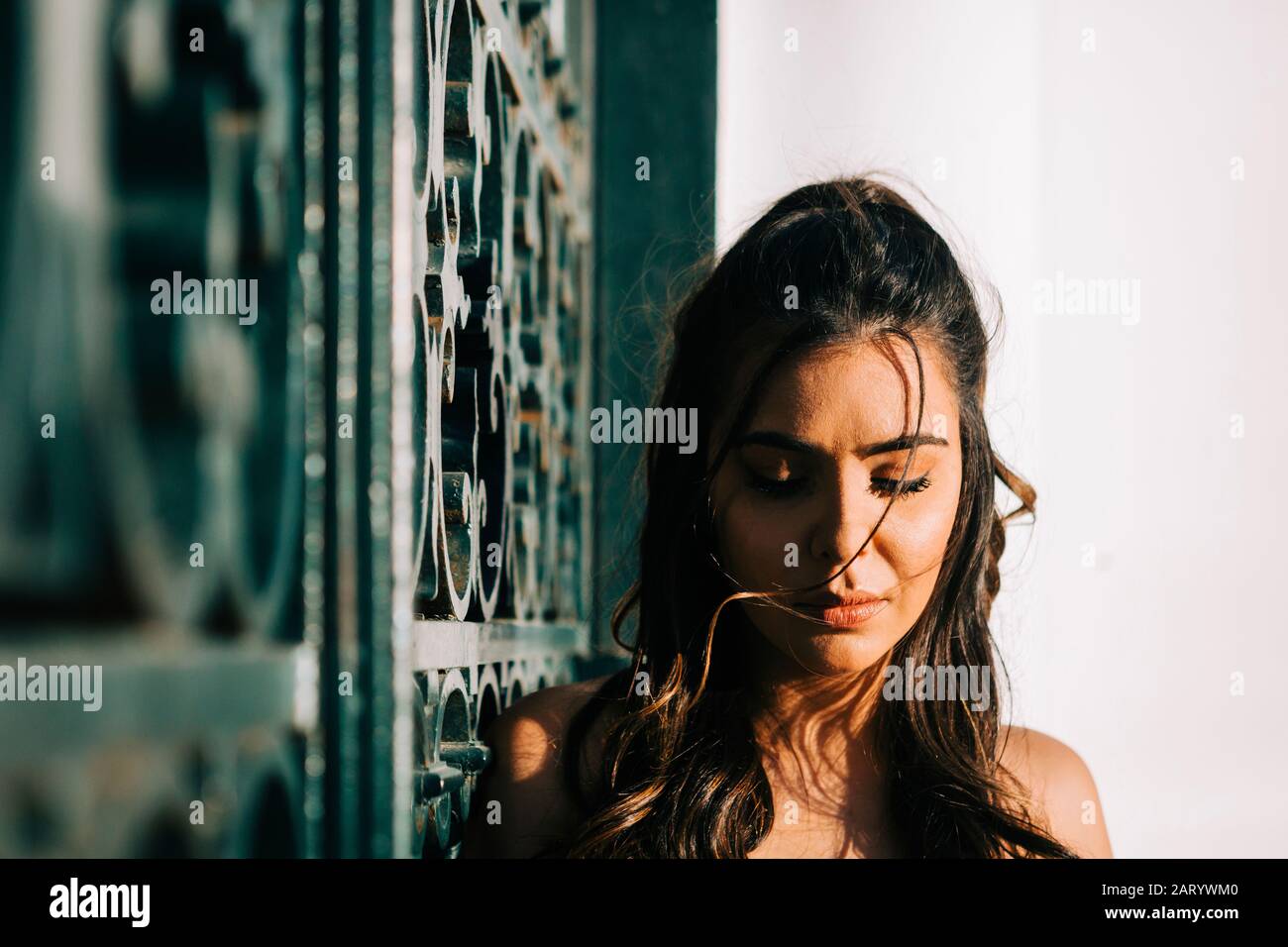 Woman looking down by metal gate Stock Photo - Alamy