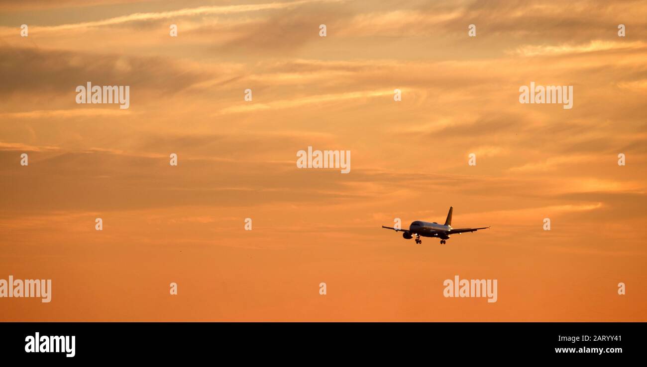 Airplane flying in sky at sunset Stock Photo - Alamy