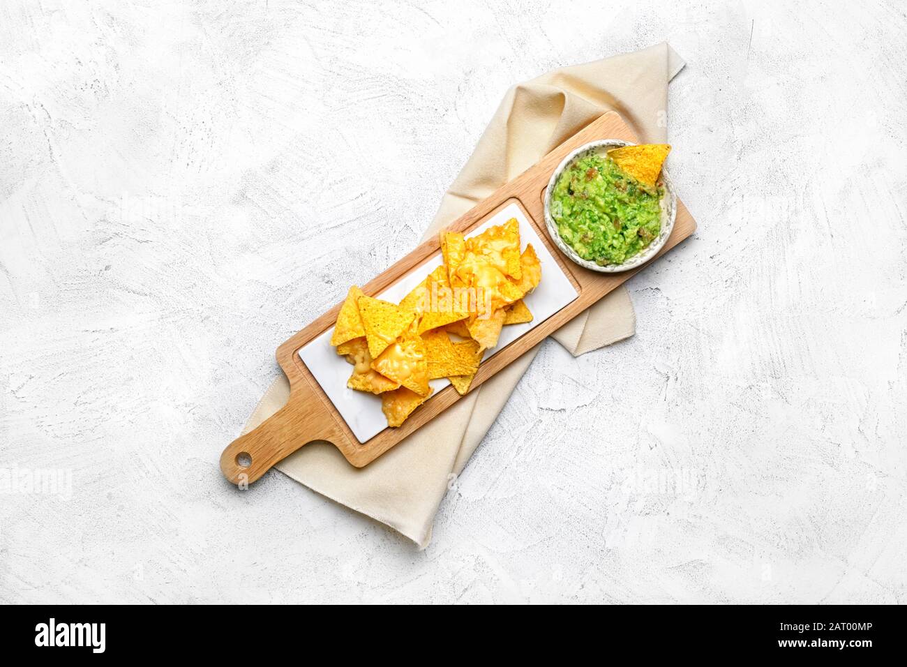Board with tasty nachos and guacamole on white background Stock Photo ...