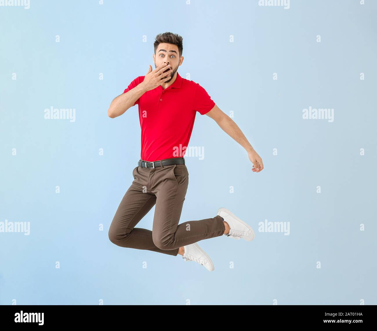Shocked jumping young man on color background Stock Photo - Alamy