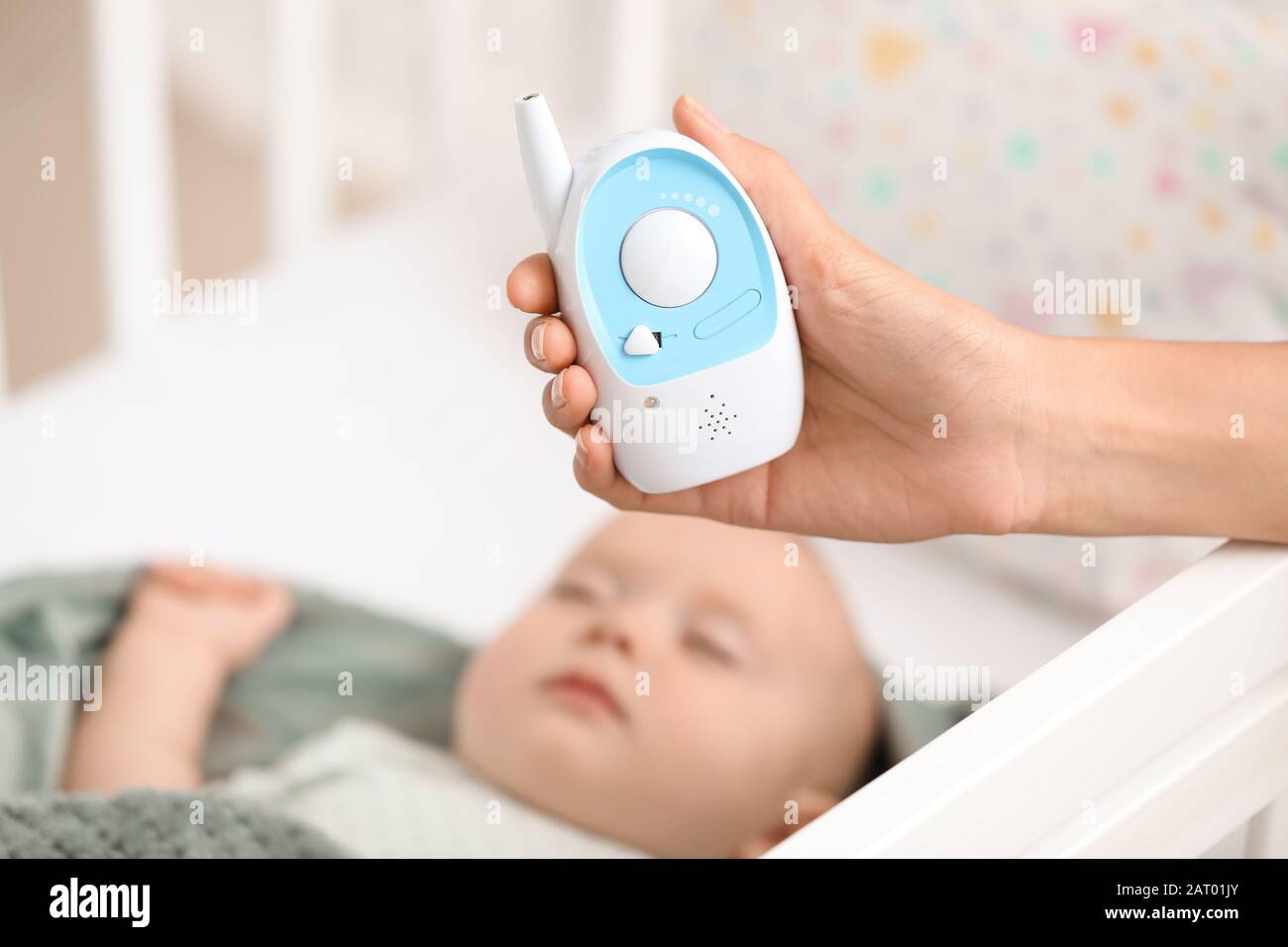 Mother with modern baby monitor near bed with sleeping child Stock ...