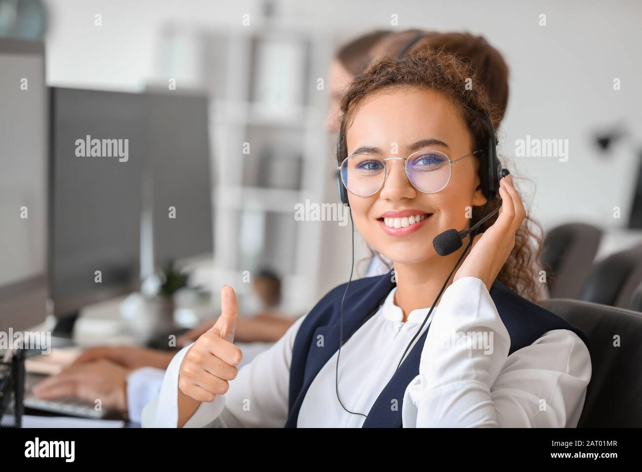 Technical support agent showing thumb-up in office Stock Photo - Alamy