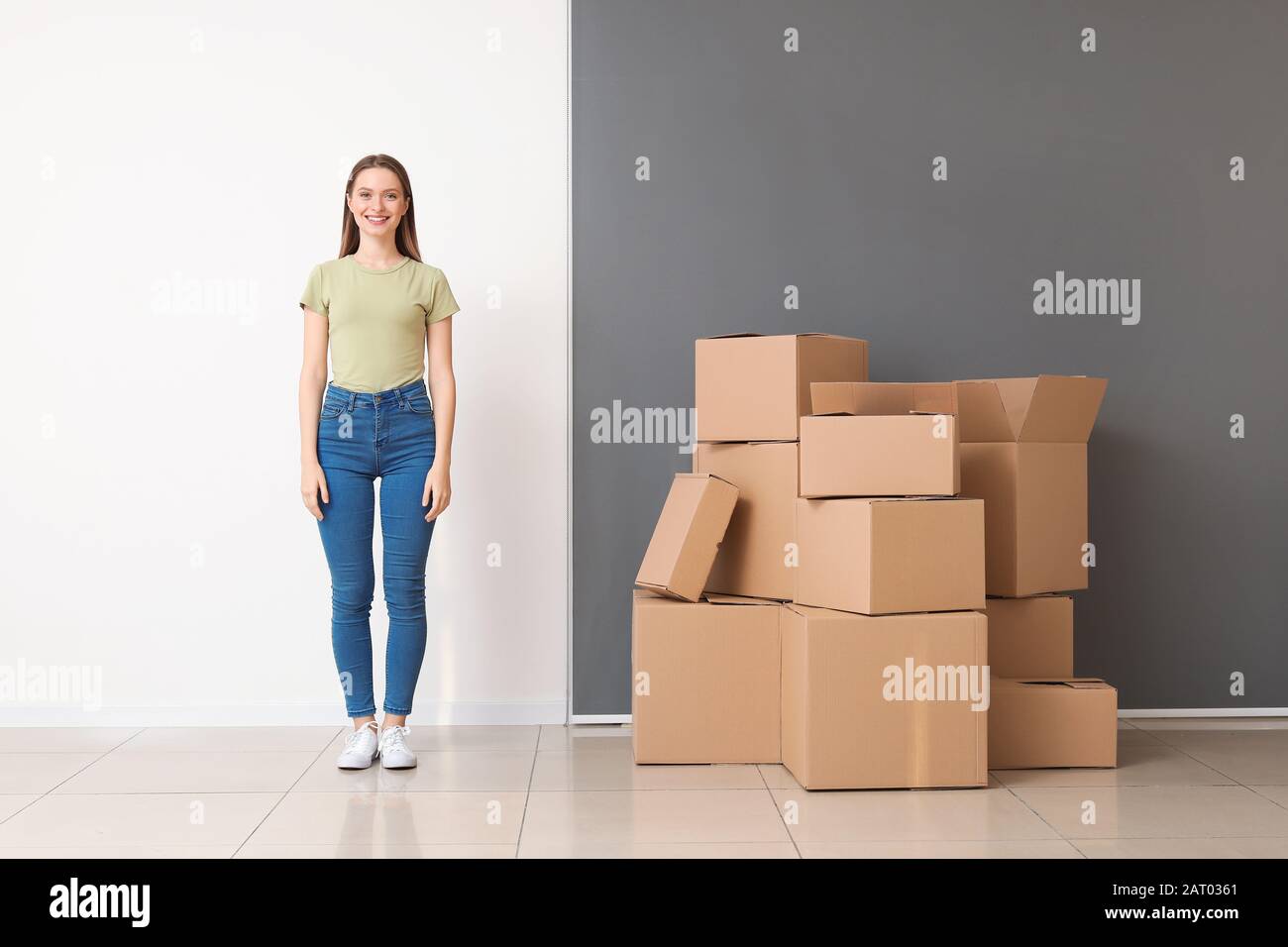 Happy young woman with moving boxes in new house Stock Photo - Alamy