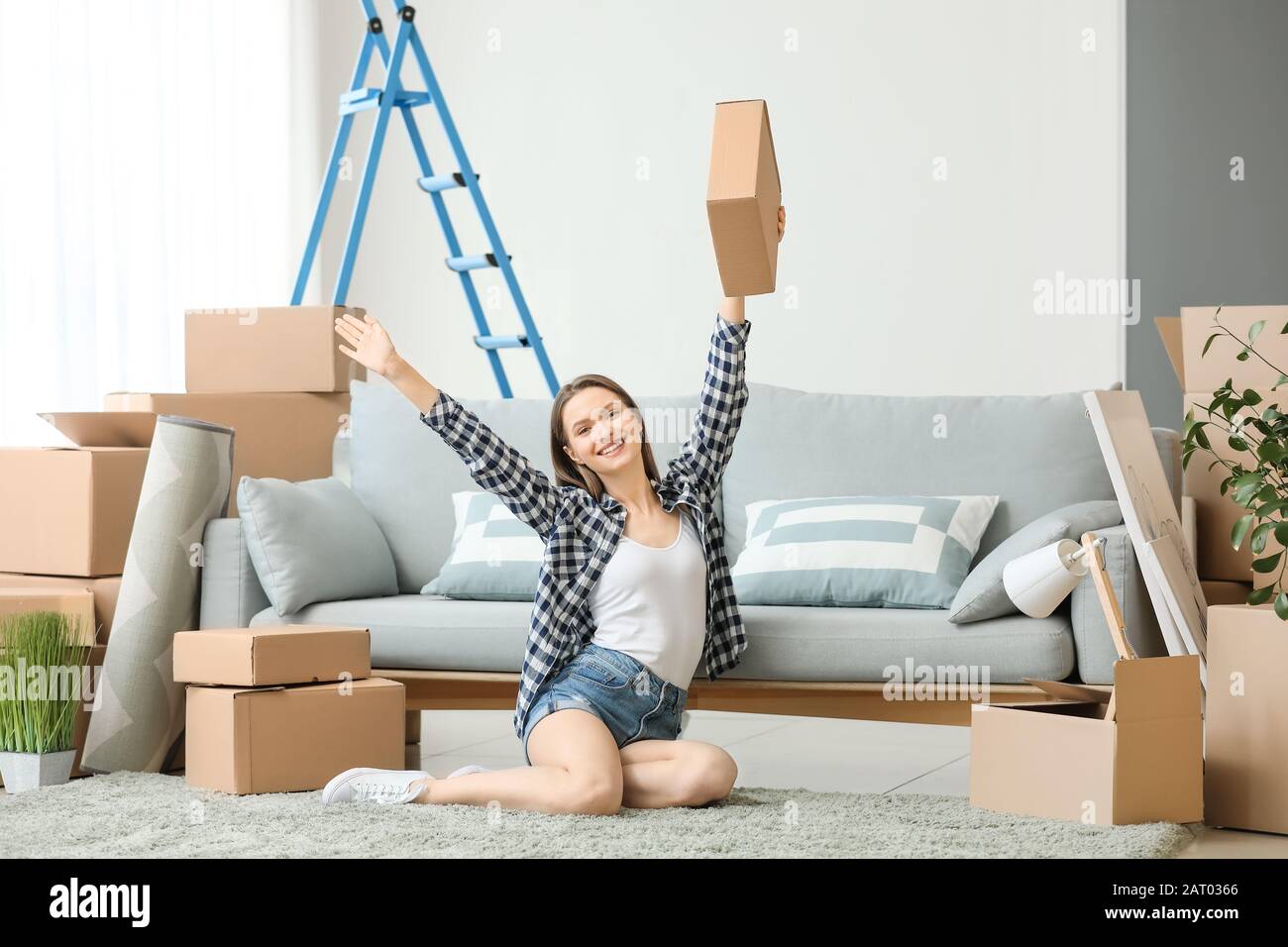 Happy young woman with moving boxes in new house Stock Photo - Alamy