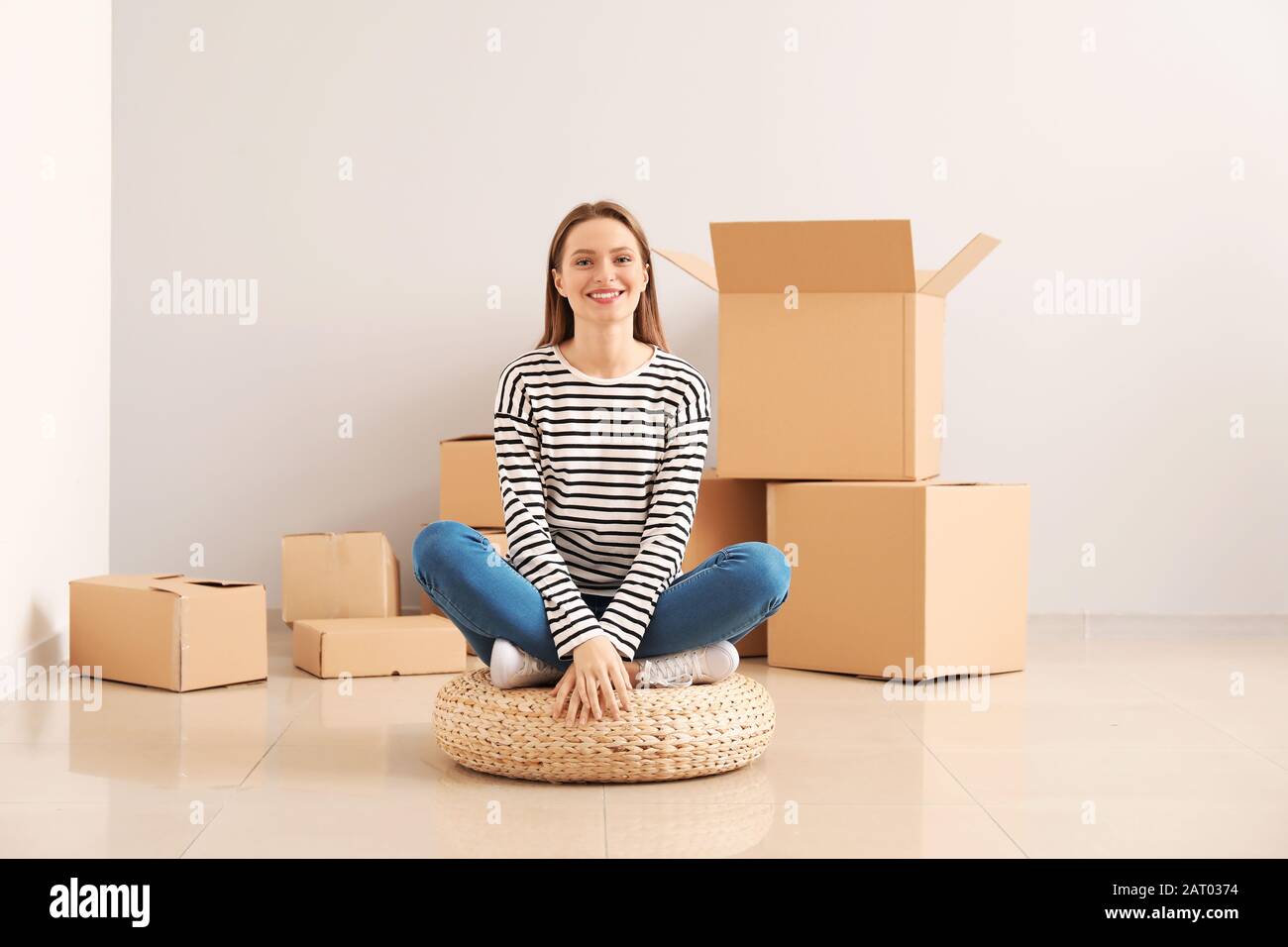 Happy young woman with moving boxes in new house Stock Photo - Alamy