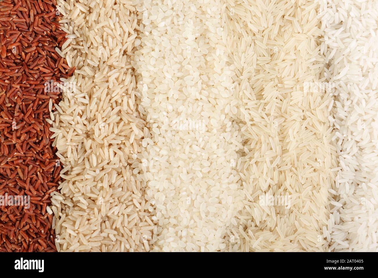 Different raw rice as background Stock Photo - Alamy