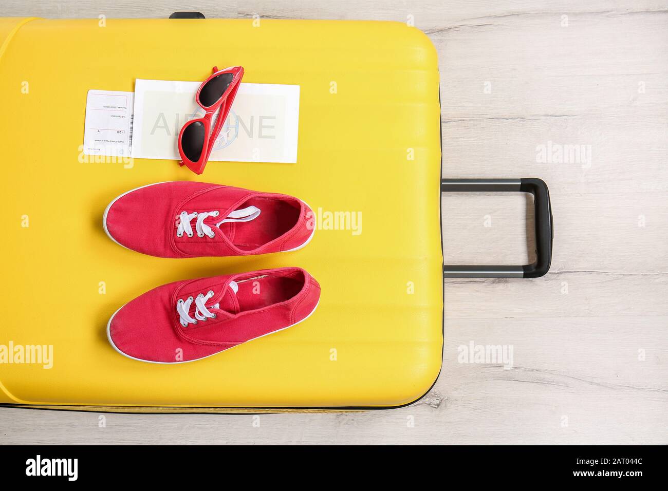 Suitcase with ticket, sunglasses and shoes on floor Stock Photo - Alamy