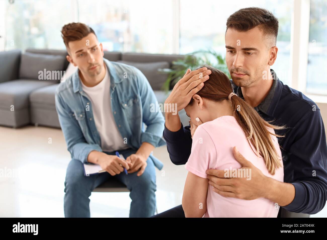 Man calming sad woman during psychological support session Stock Photo ...