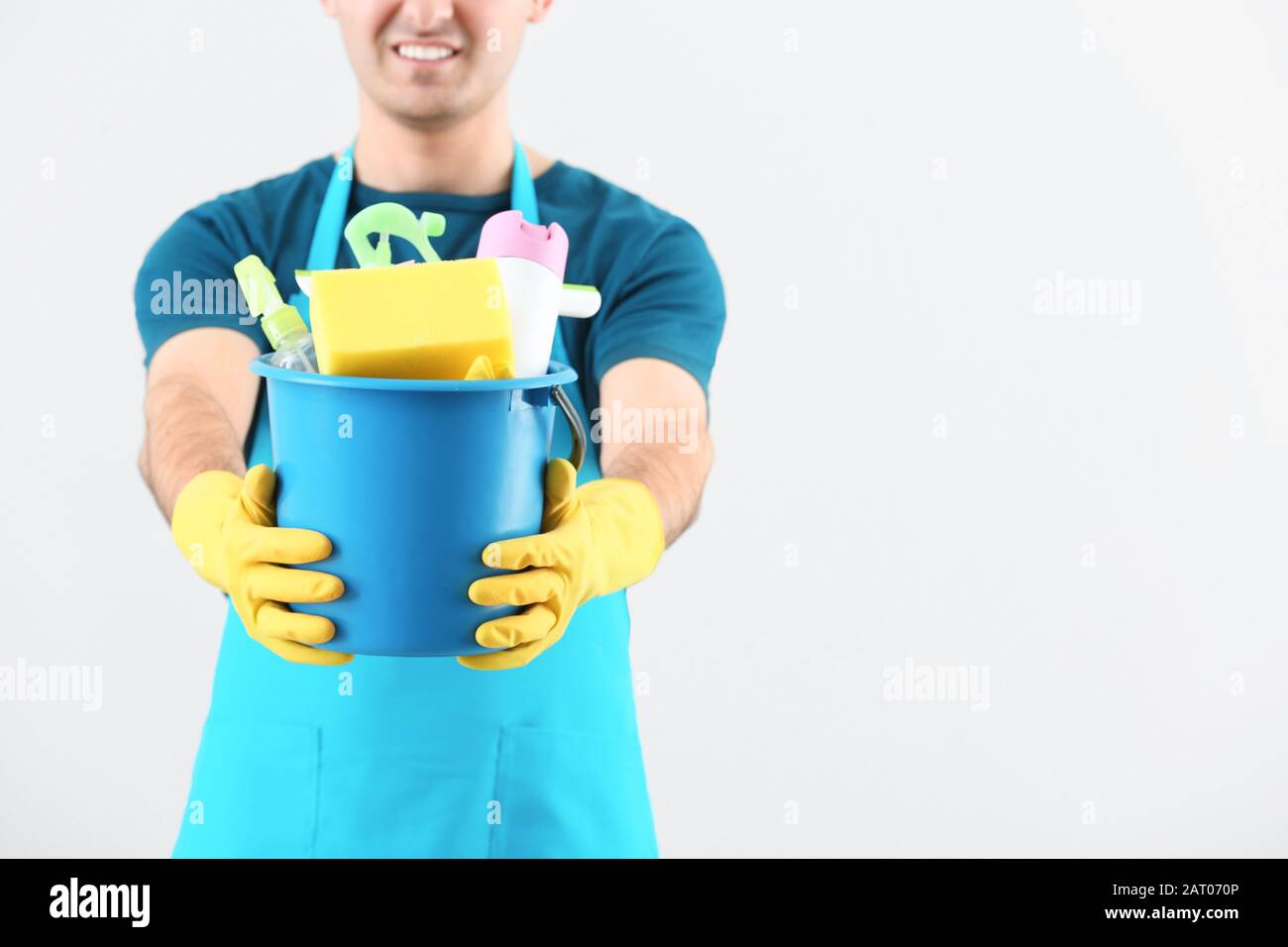 Janitor with cleaning supplies on light background Stock Photo - Alamy