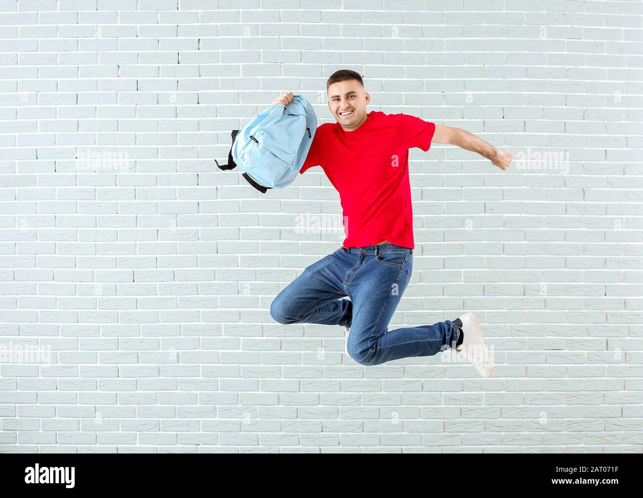 Happy young man jumping against wall hi-res stock photography and ...