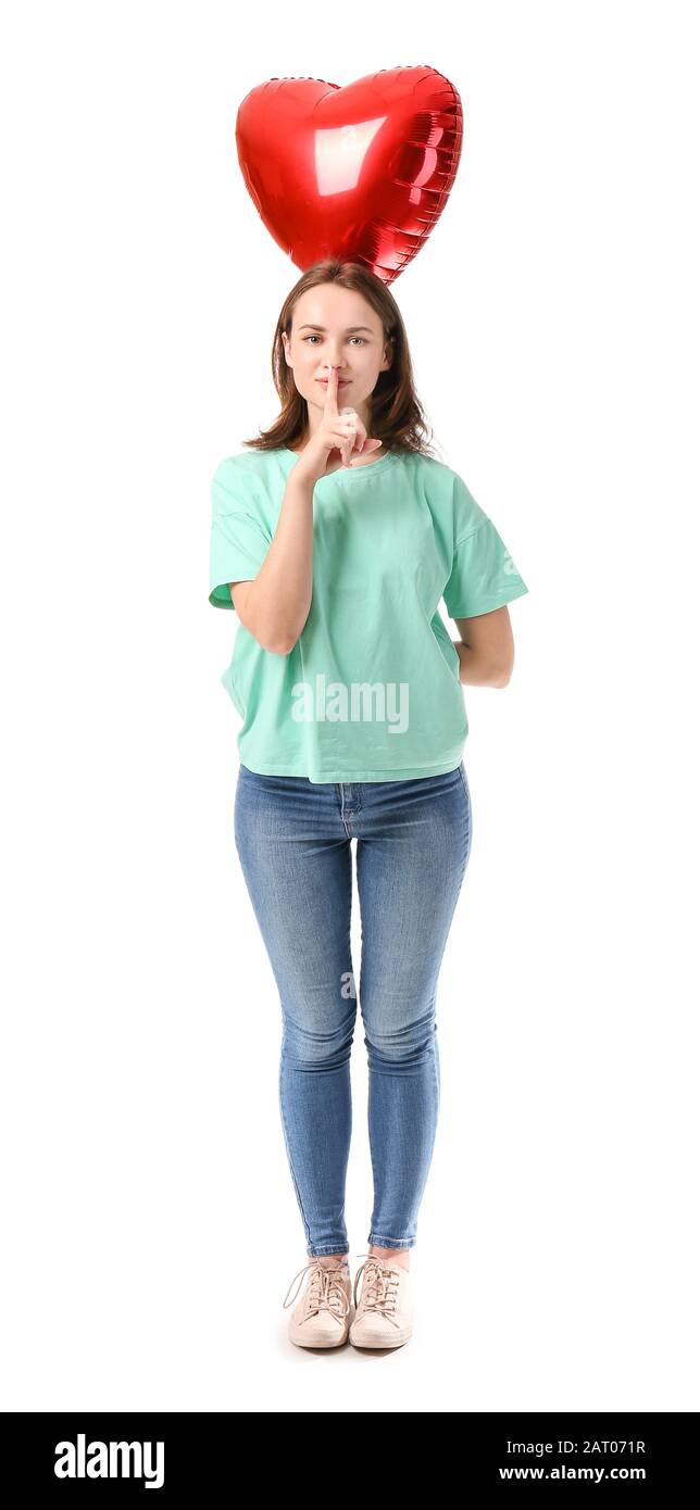 Beautiful young woman with heart-shaped balloon showing silence gesture ...
