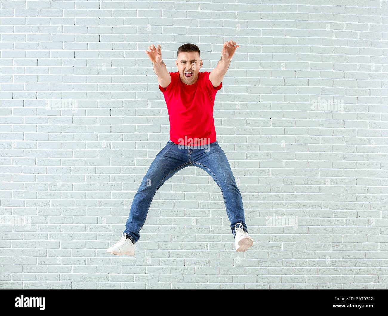 Jumping young man against brick wall Stock Photo - Alamy