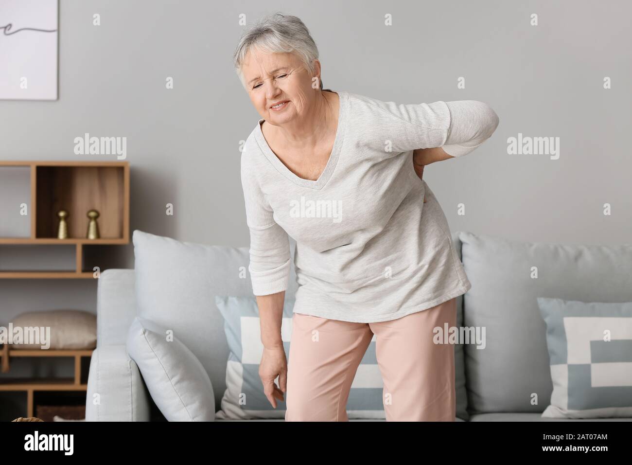 Senior woman suffering from back pain at home Stock Photo - Alamy