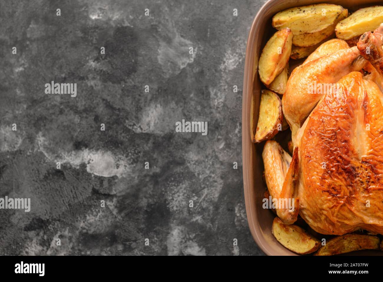 Dish with baked chicken and potato on dark background Stock Photo - Alamy