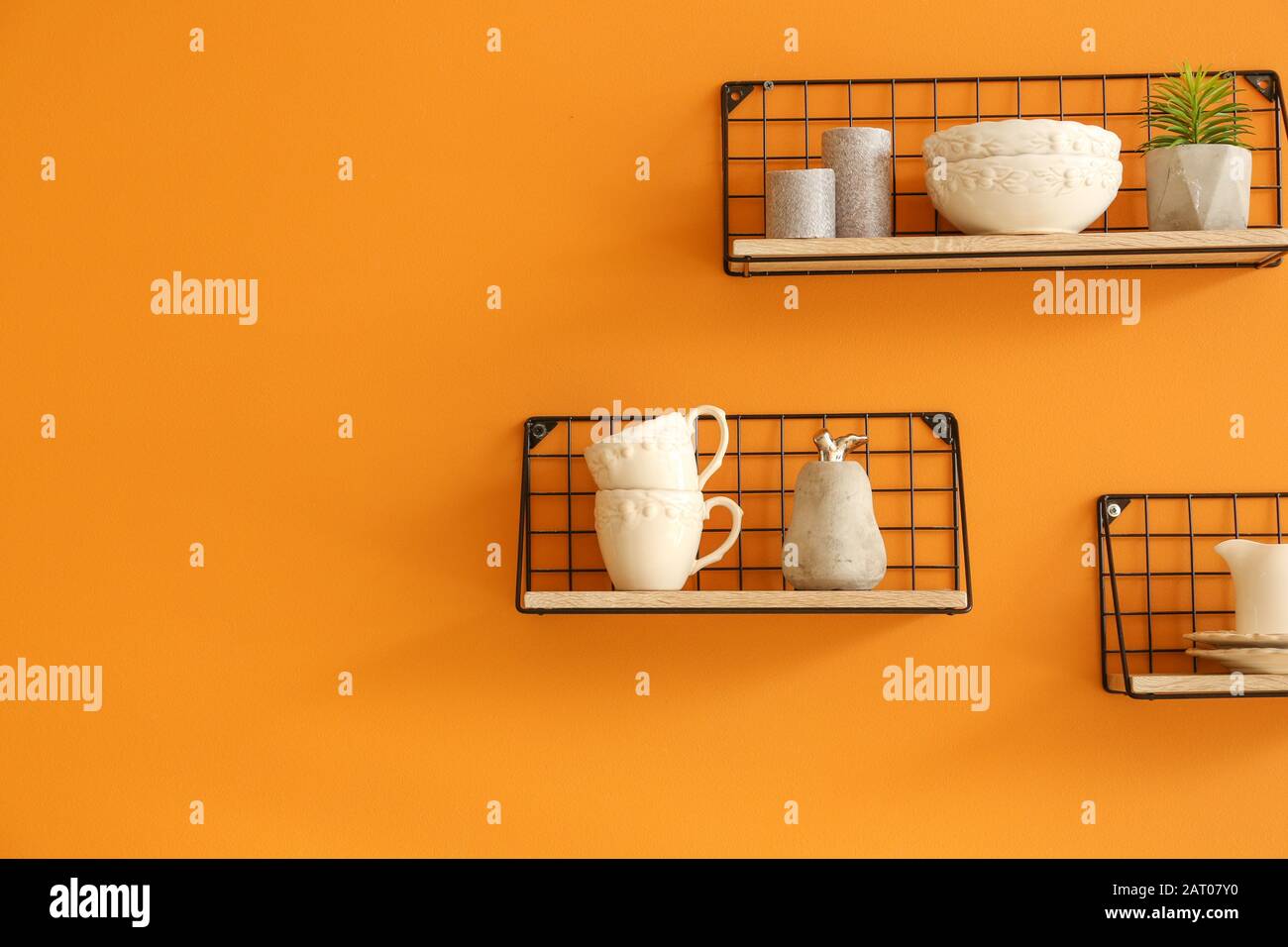 Shelves with tableware hanging on color wall Stock Photo - Alamy