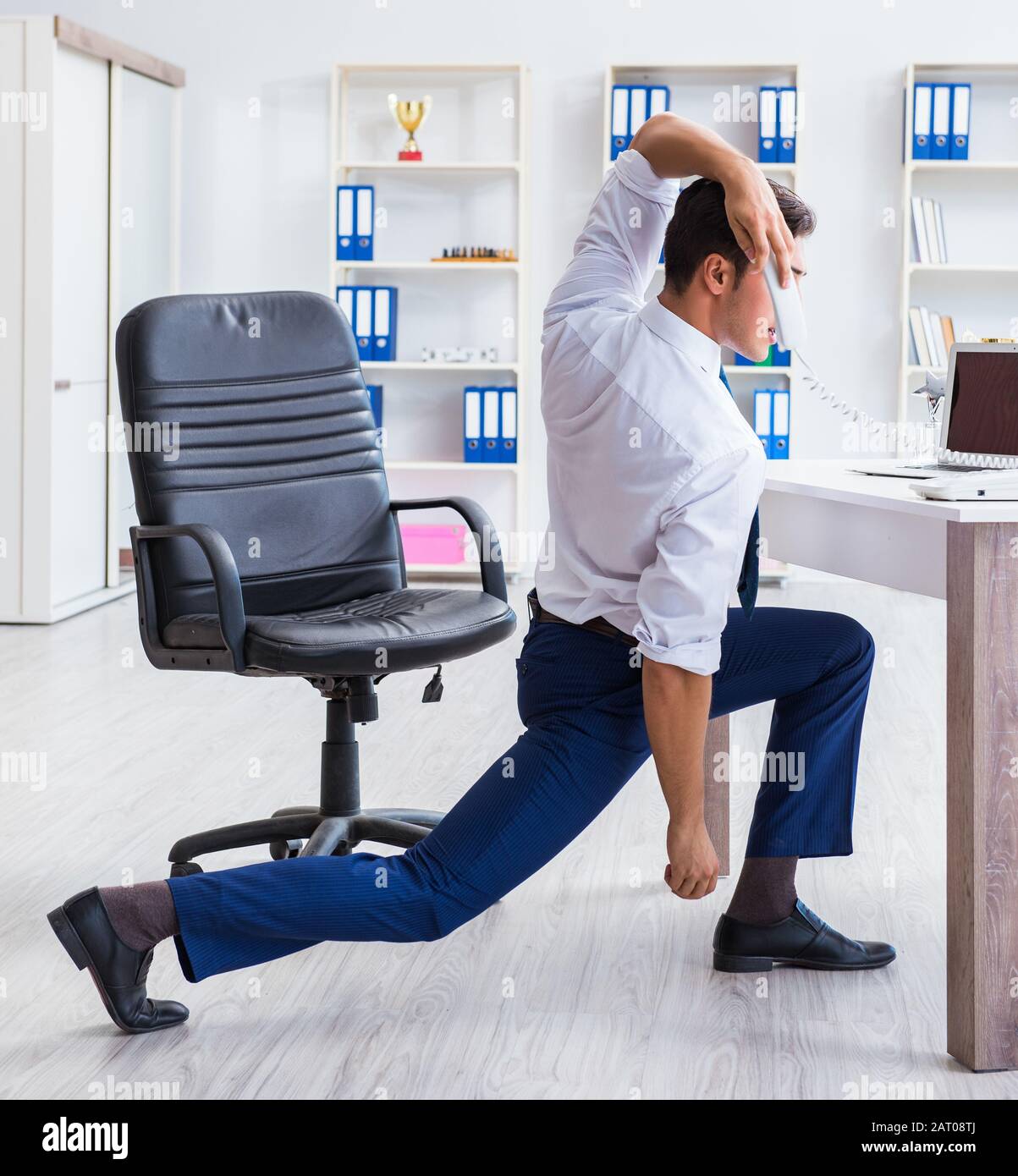 The young businessman doing sports stretching at workplace Stock Photo ...