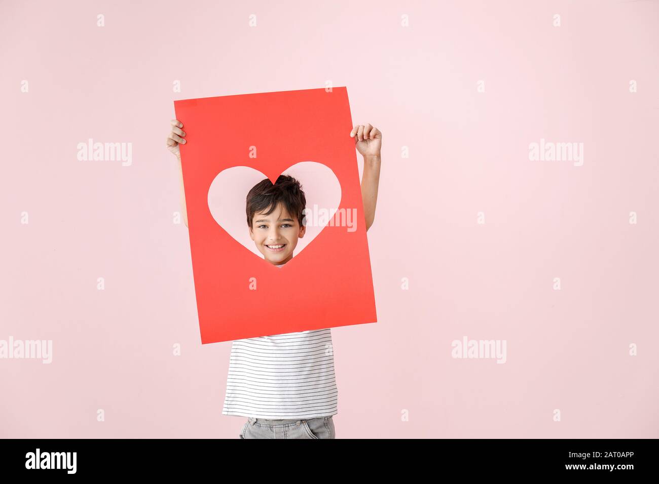 Cute little boy holding paper sheet with hole in shape of heart on ...