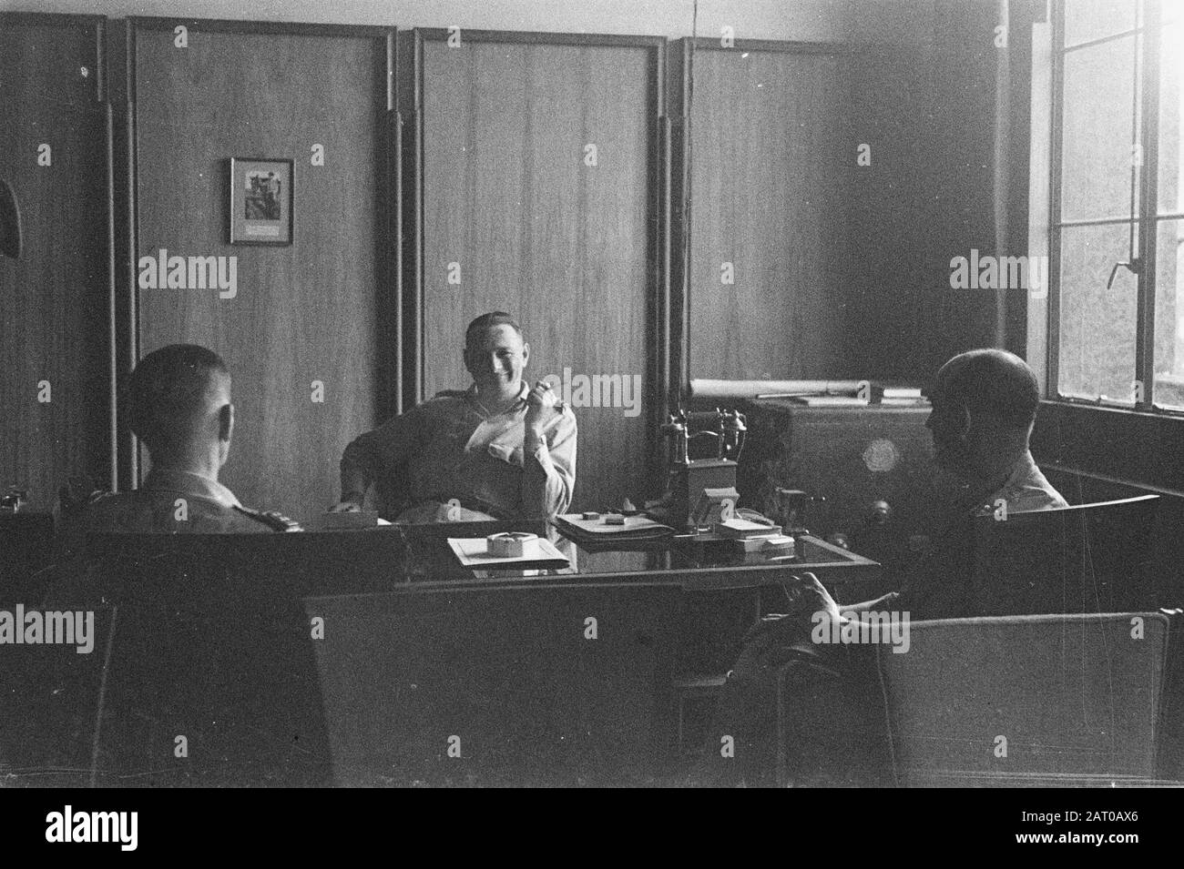 Three officers in conversation at the office, behind desk army ...