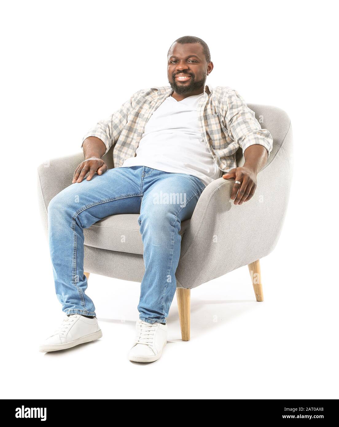 African-American man relaxing in armchair against white background ...