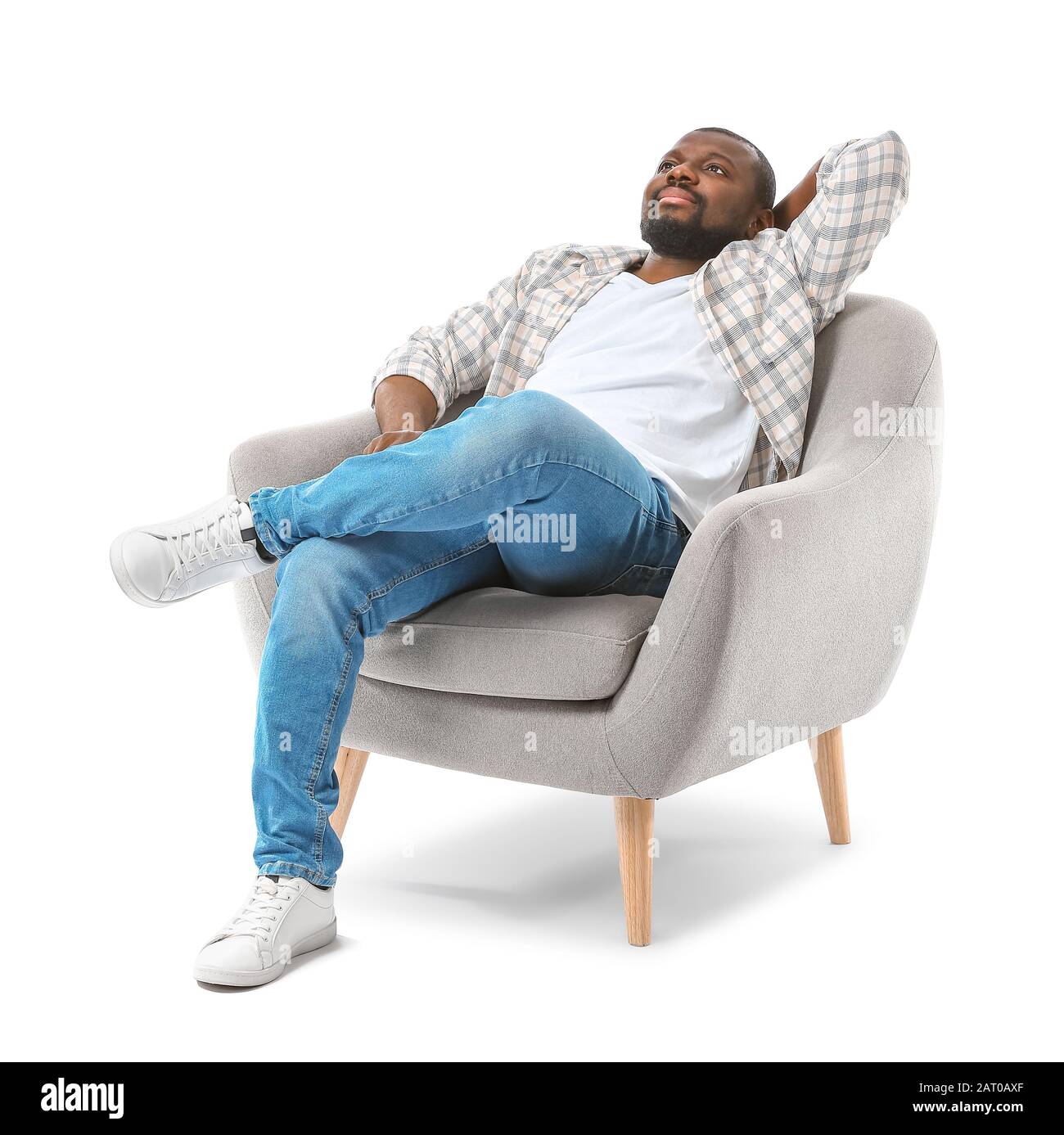 African-American man relaxing in armchair against white background ...