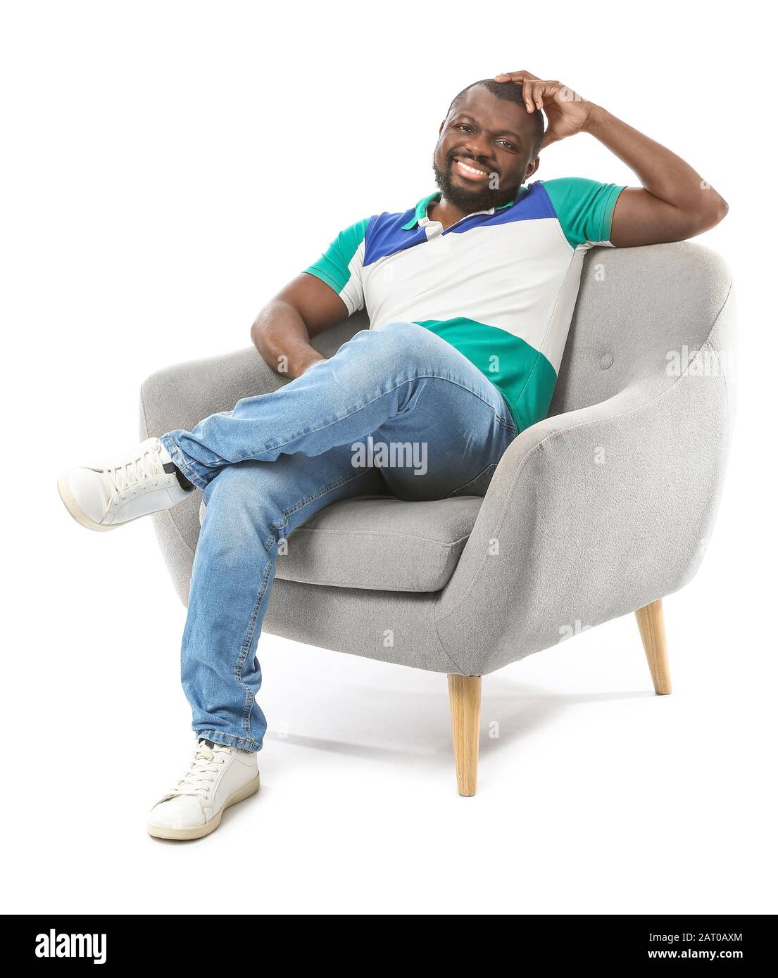 African-American man relaxing in armchair against white background ...