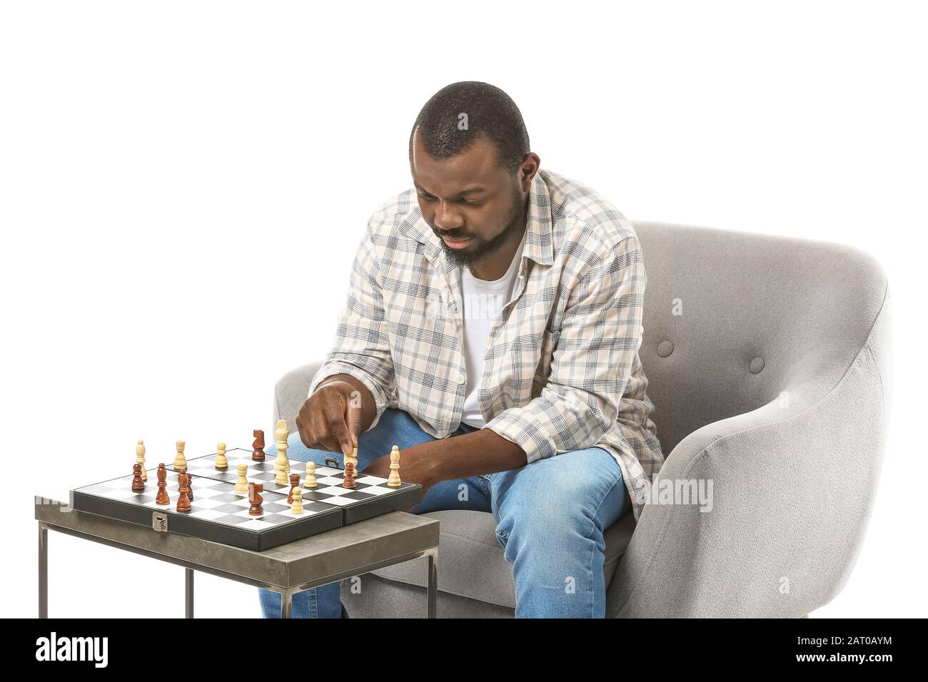 African-American man playing chess while sitting in armchair against ...