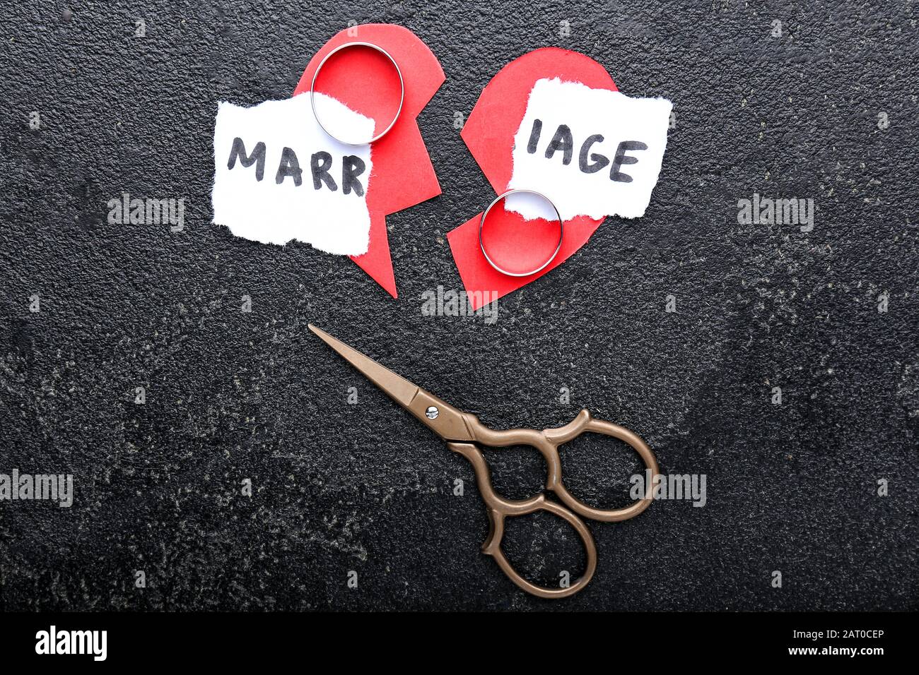 Broken heart, rings, scissors and torn paper with word MARRIAGE on dark ...