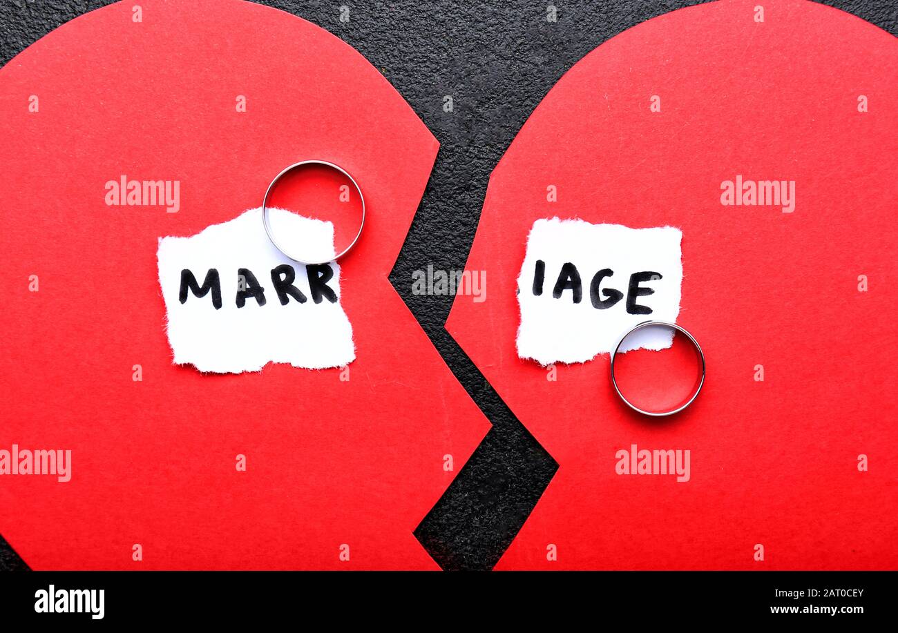 Broken heart, rings and torn paper with word MARRIAGE on dark ...